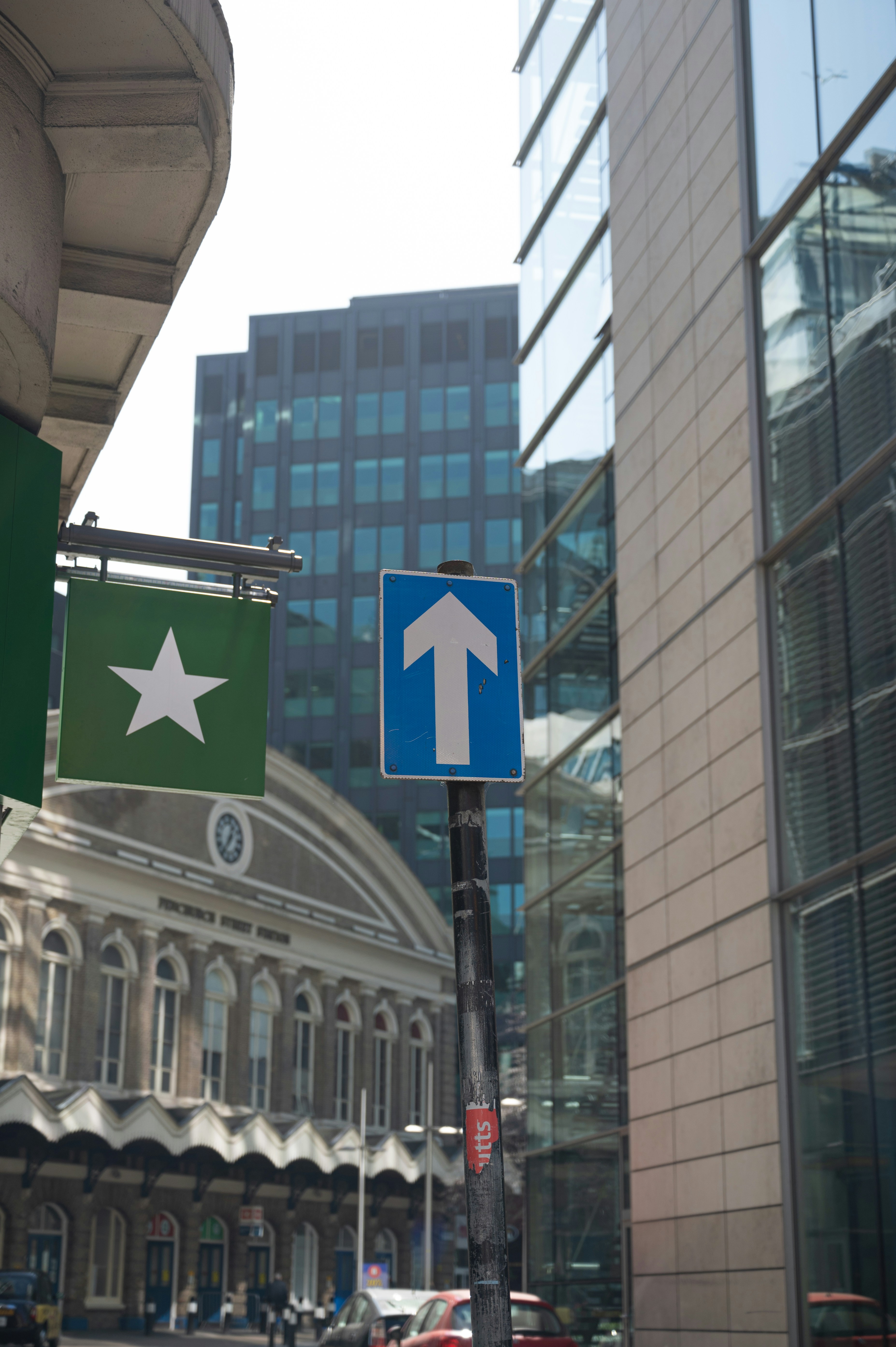 Blue Arrow Amid Glass Facades: A Street Sign Portrait