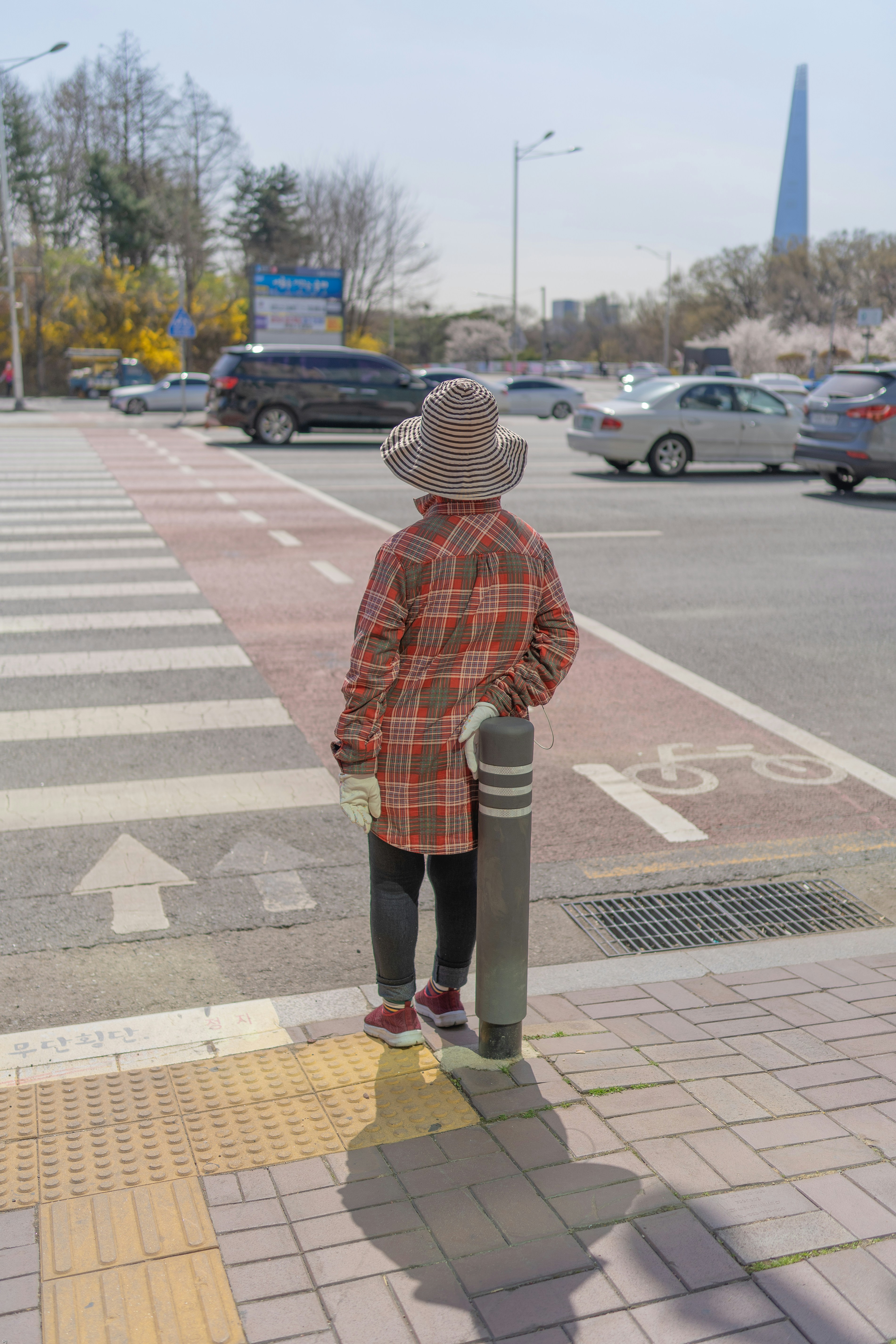 A woman who stops and waits for a crosswalk signal.