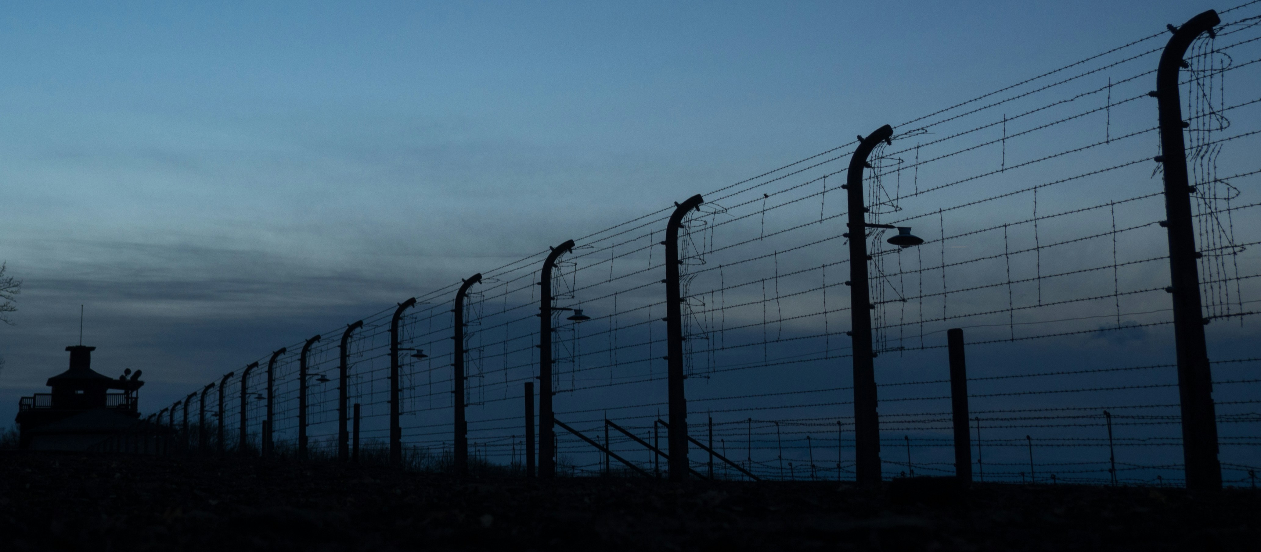 Silhouetted Fenceline at Dusk: The Long Reach of Containment