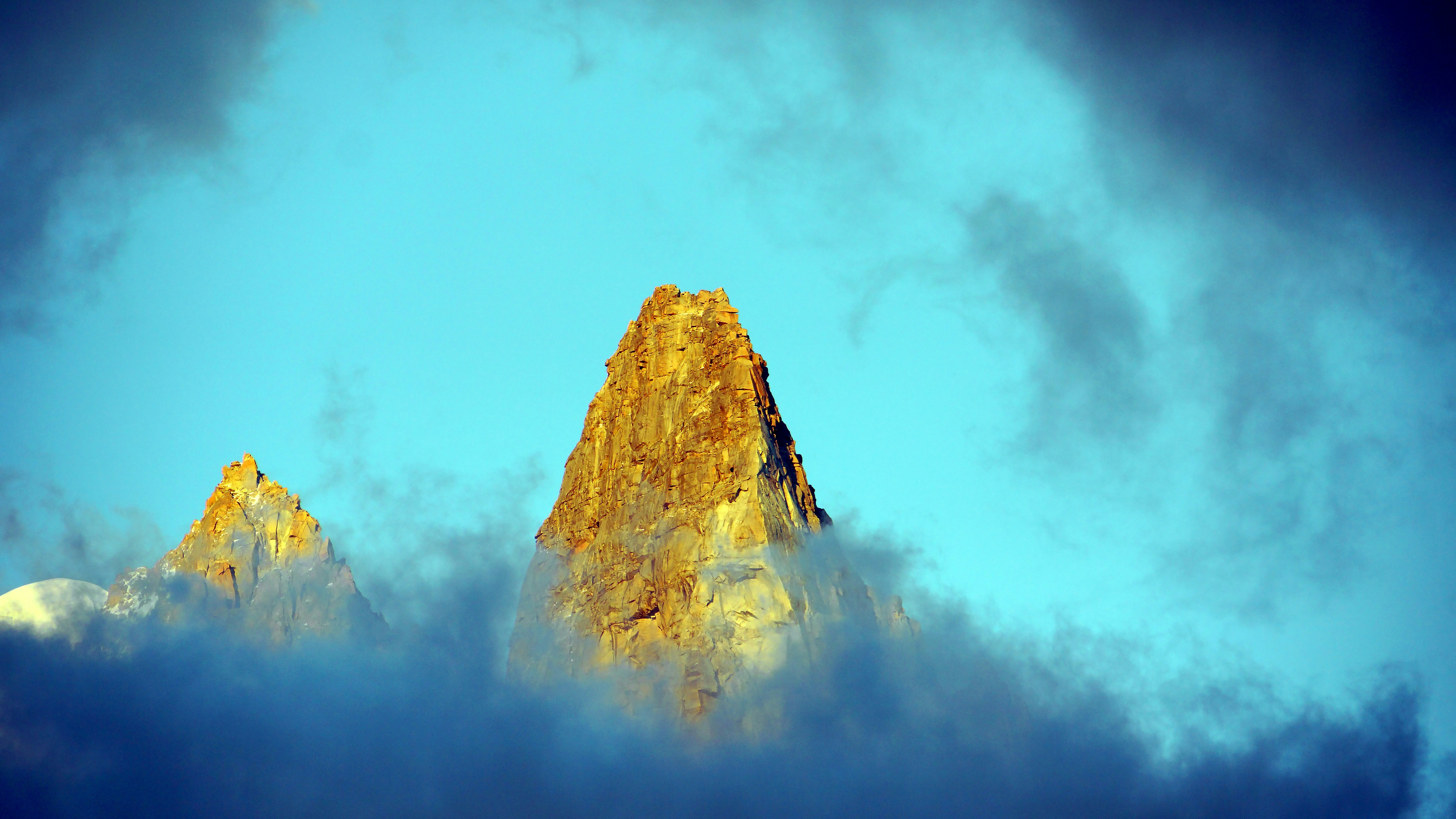 Gold-Tipped Summit Rising Through a Cyan Sea of Clouds