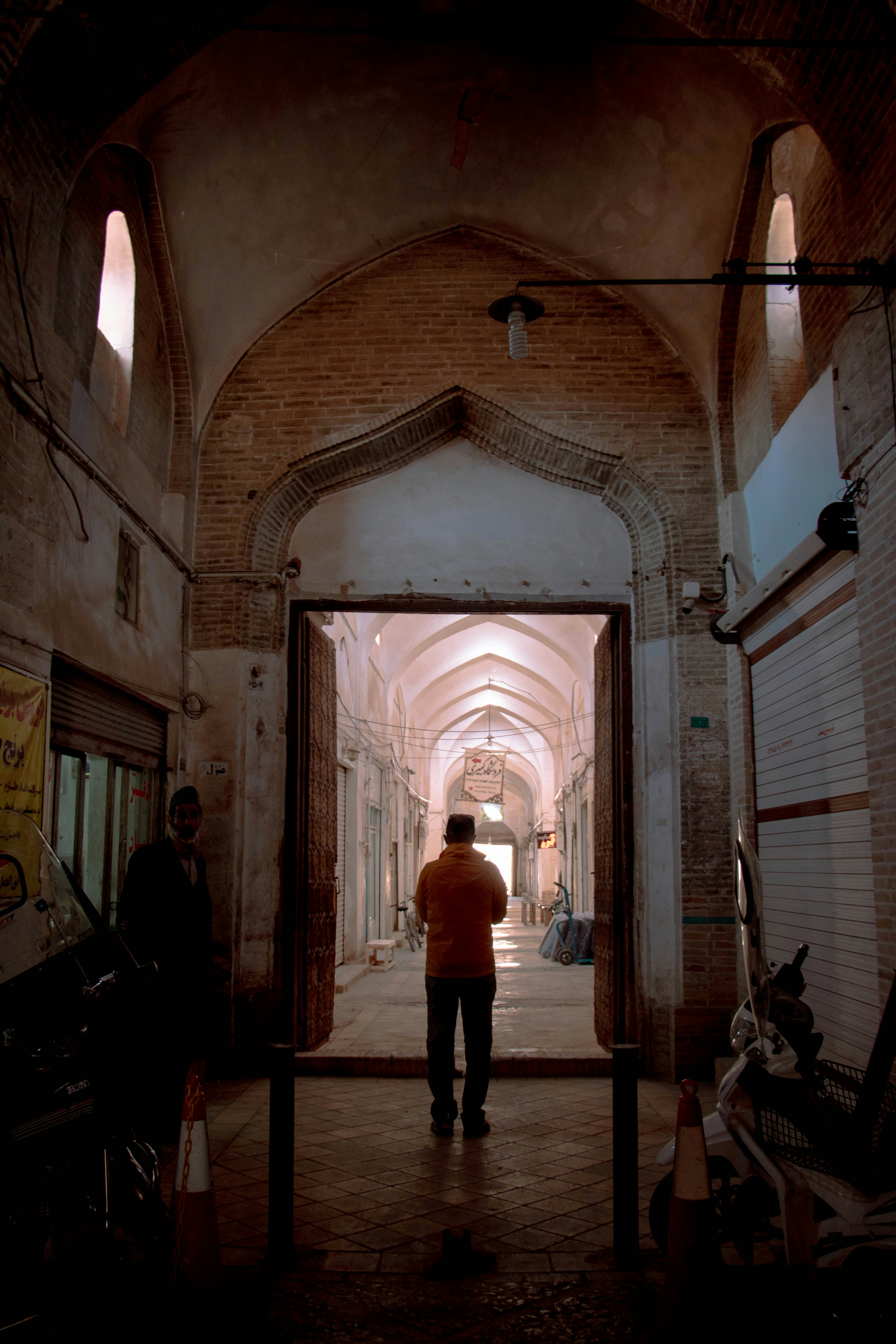 Amber-Clad Silhouette in a Vaulted Market Archway
