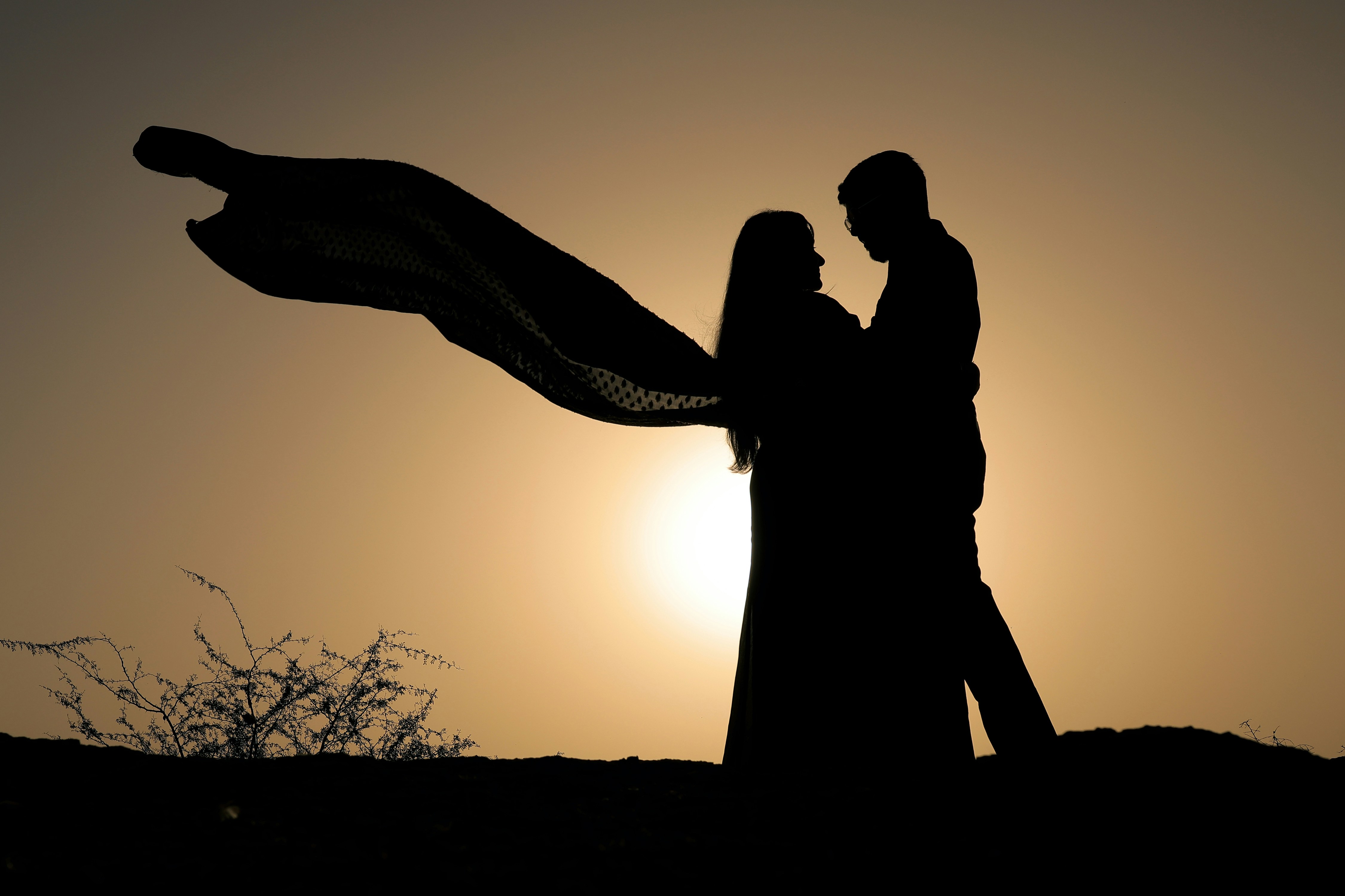 silhouette of man and woman kissing during sunset