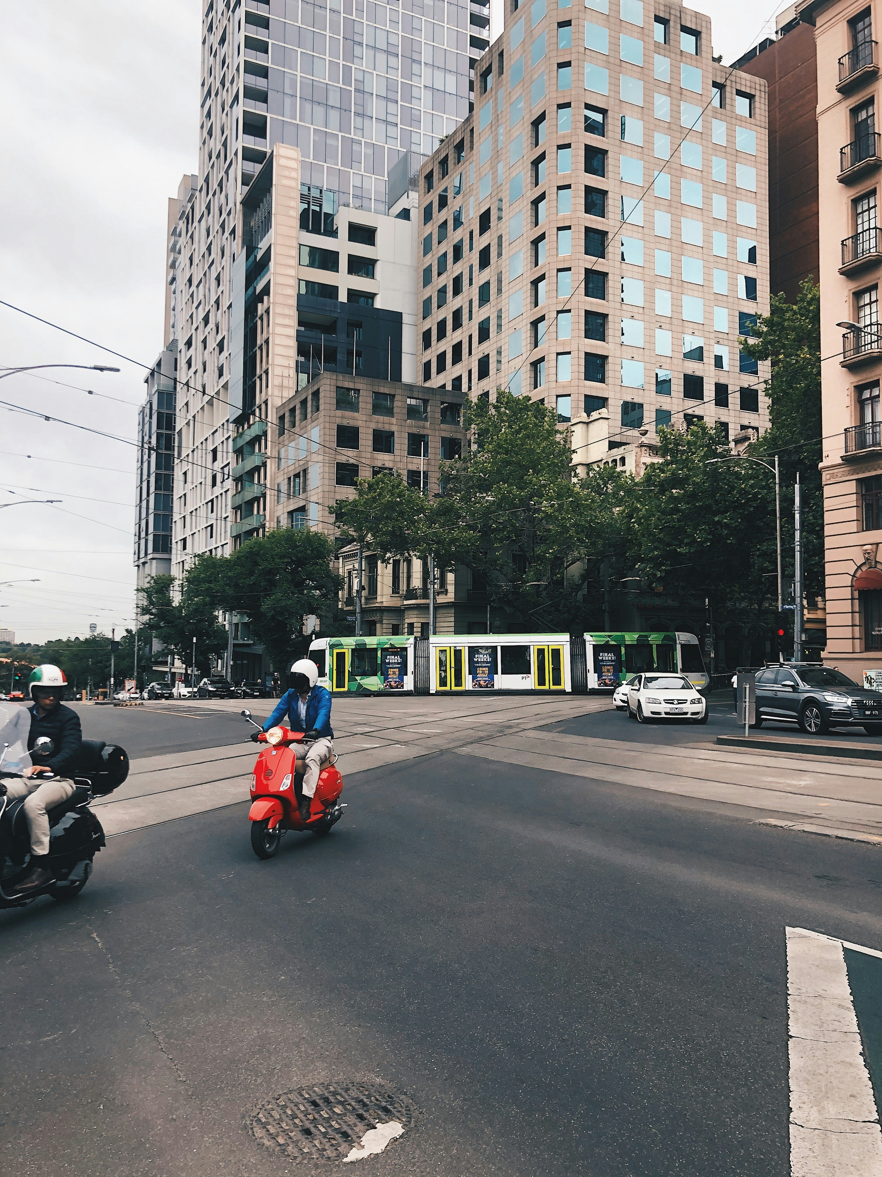 City Street Pulse: A Bright Red Vespa Amid Towering Facades