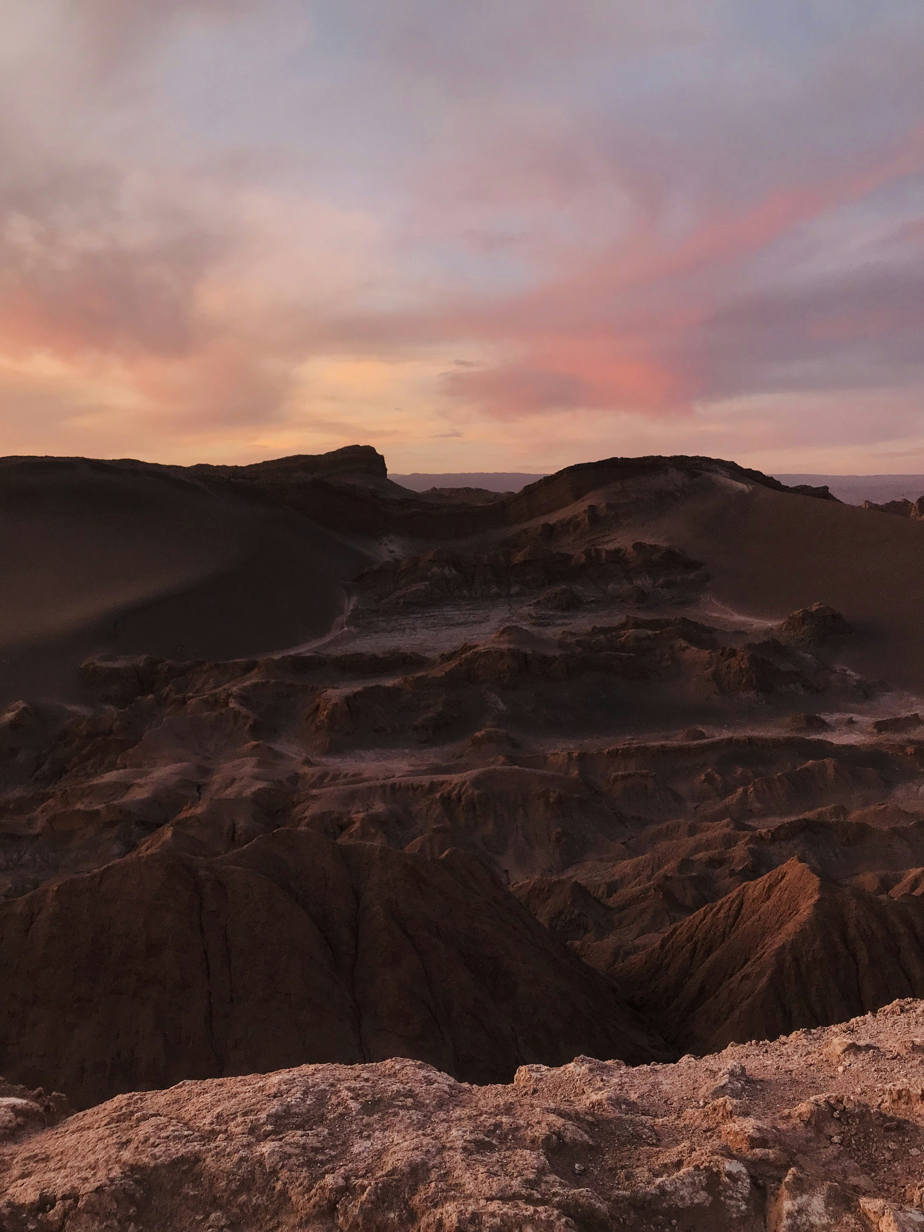 Dramatic landscape showcasing rugged terrain beneath a pastel sunset sky, highlighting the textures of the earth's surface.