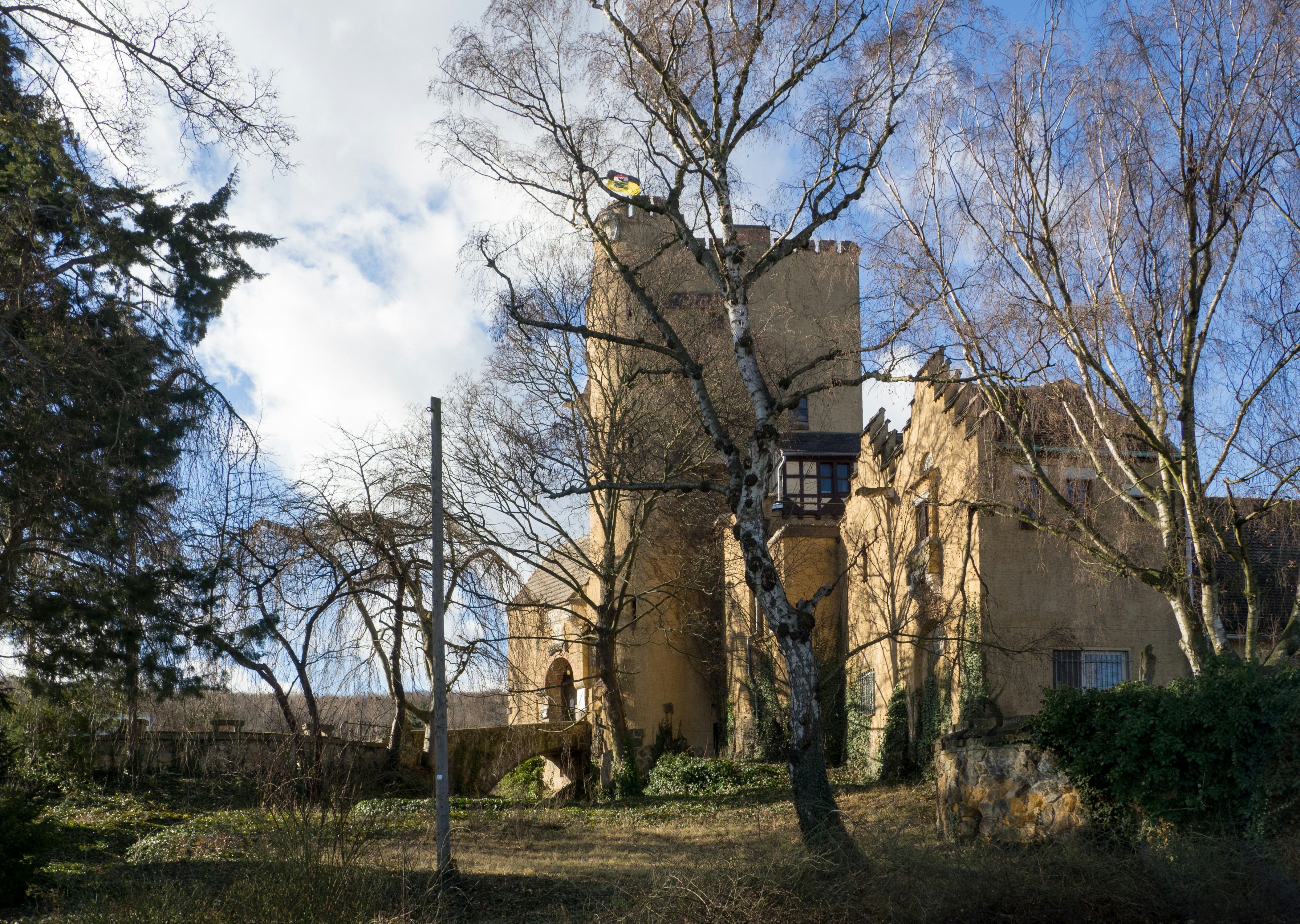 Ancient stone building surrounded by bare winter trees under a partly cloudy sky.