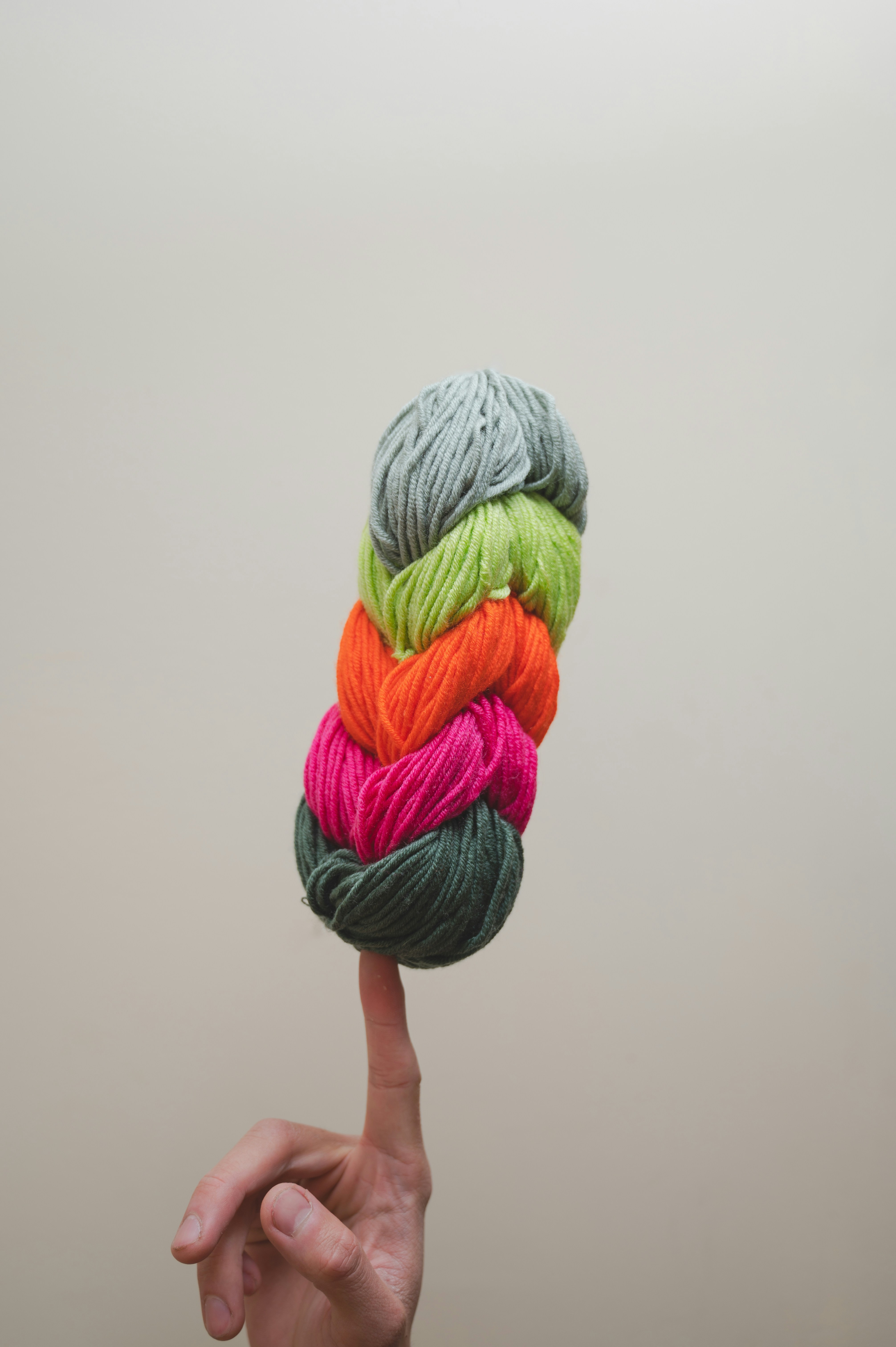Fingertip Rainbow: A Tower of Neon Skeins Poised on One Finger