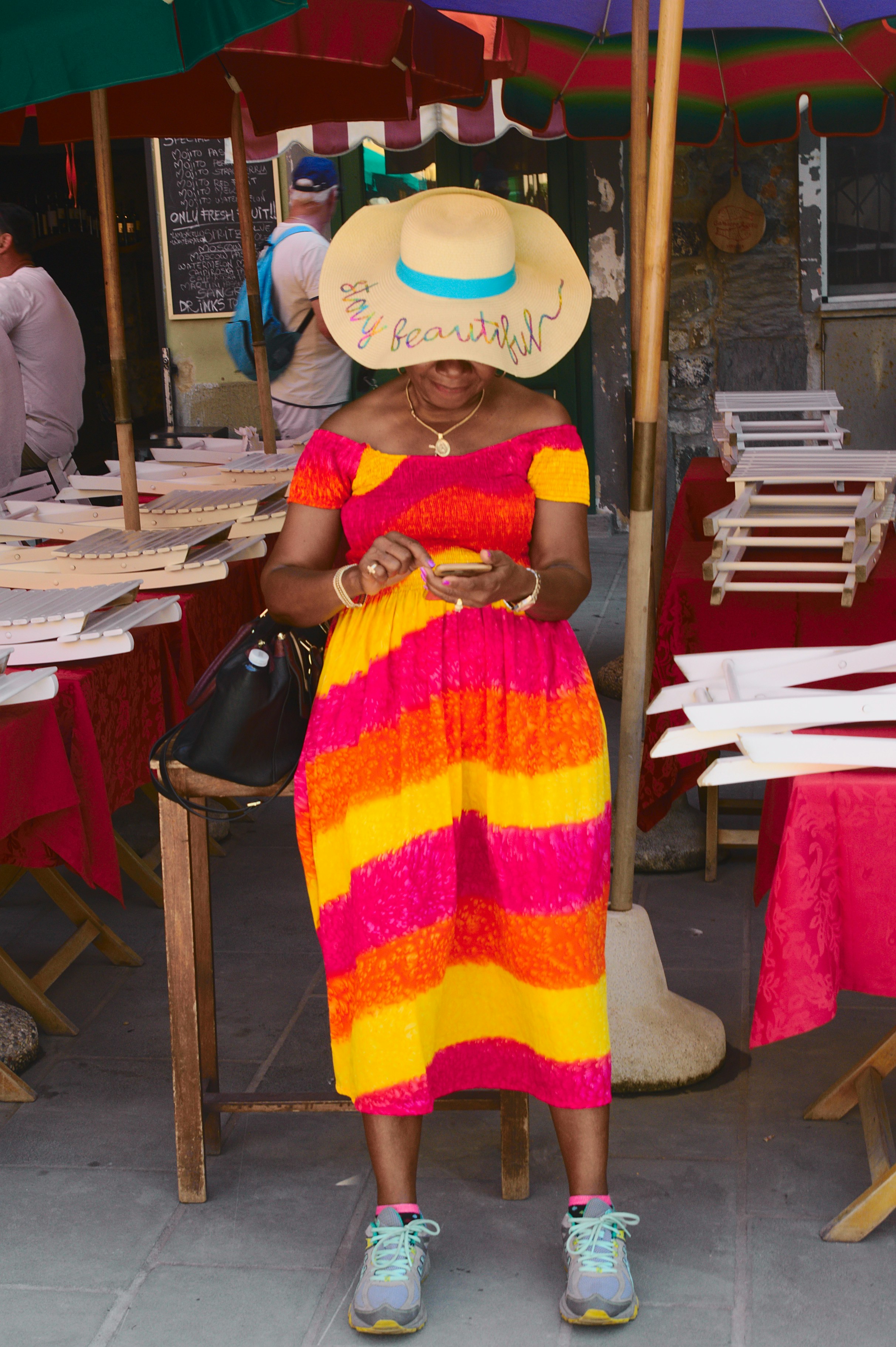 woman in yellow and red sleeveless dress wearing white sun hat