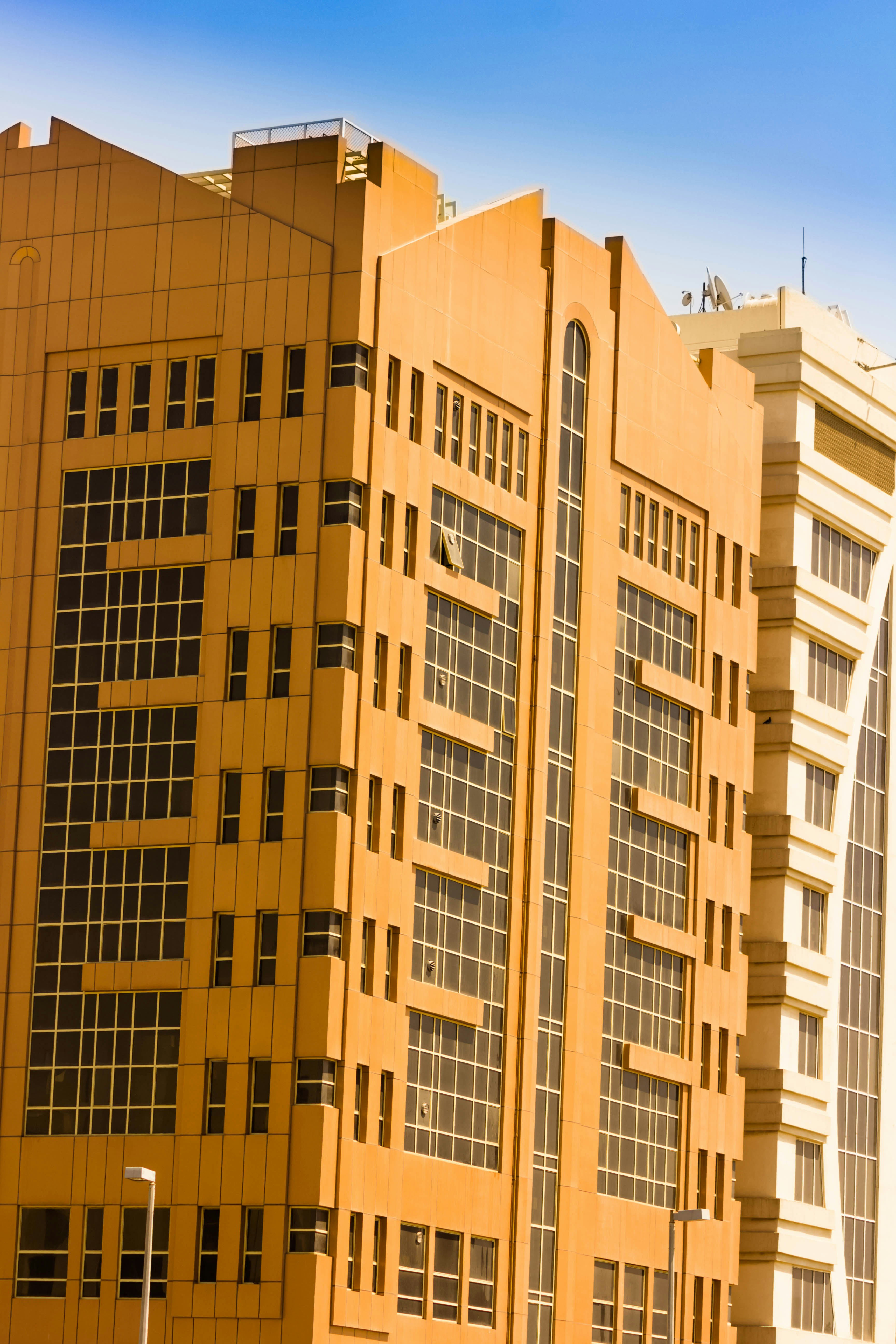 Modern architectural design featuring a striking orange facade with large windows, set against a clear blue sky.