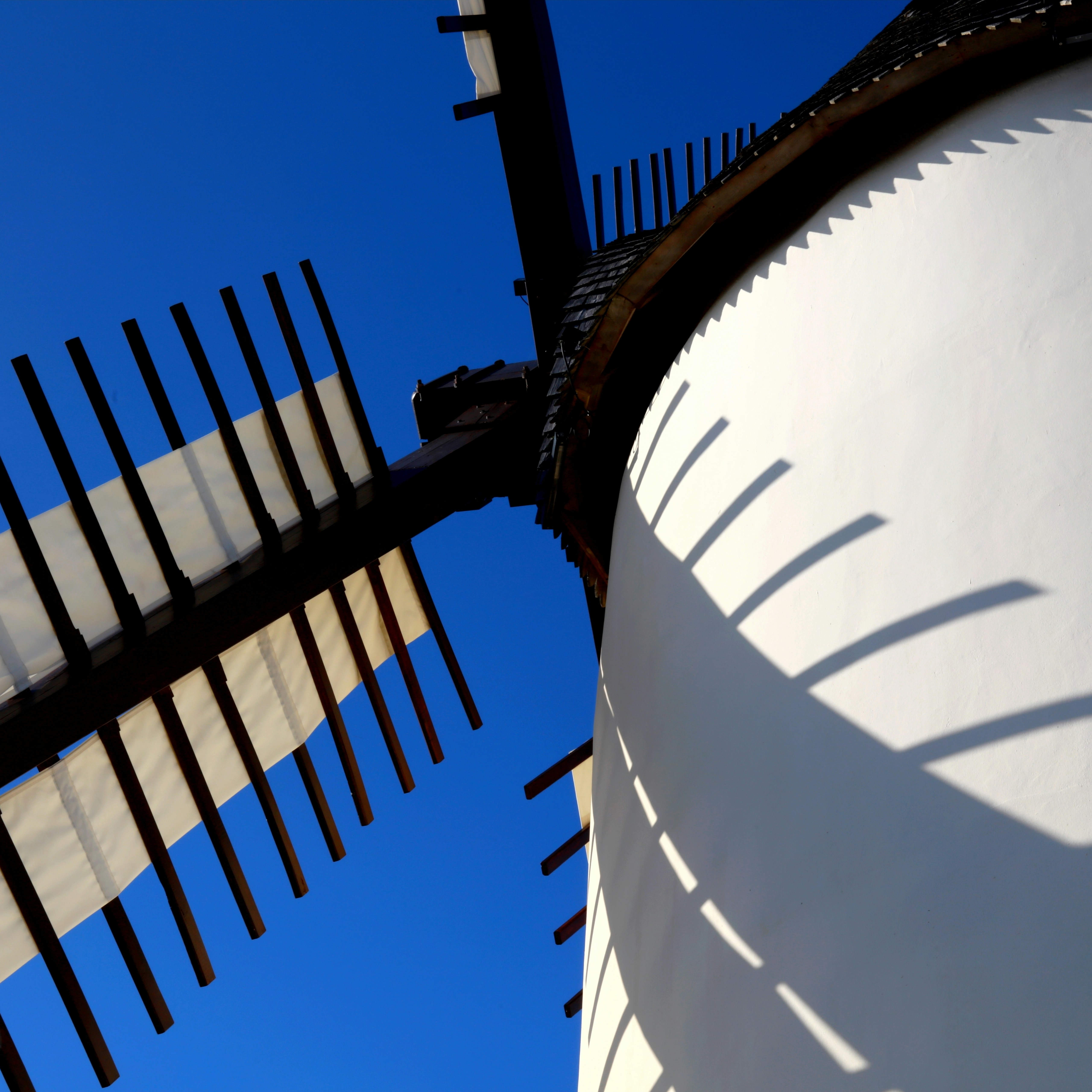 Shadowed Rails on a White Cylinder Under a Pristine Blue Sky