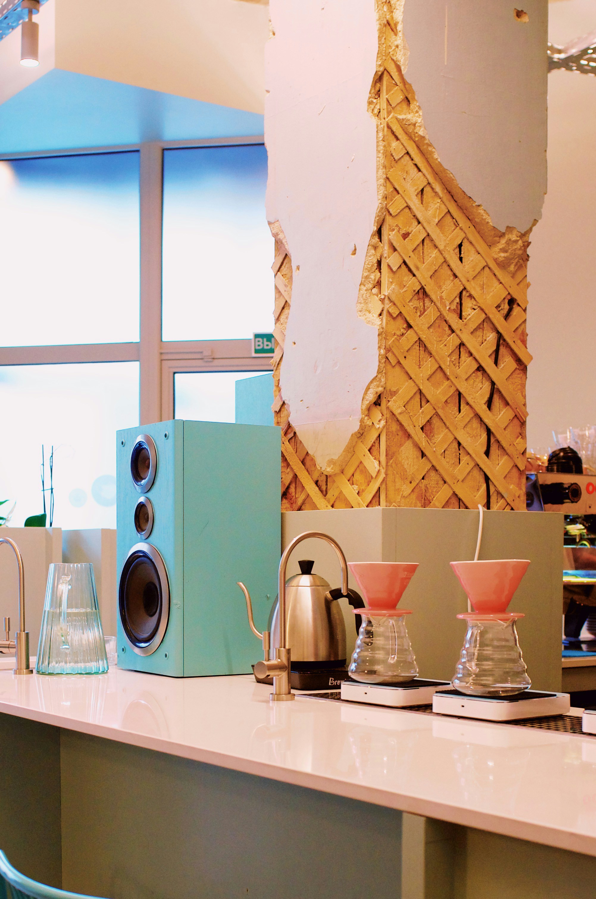 Turquoise Speaker Anchors a Quiet Coffee Bar Under a Lattice Pillar