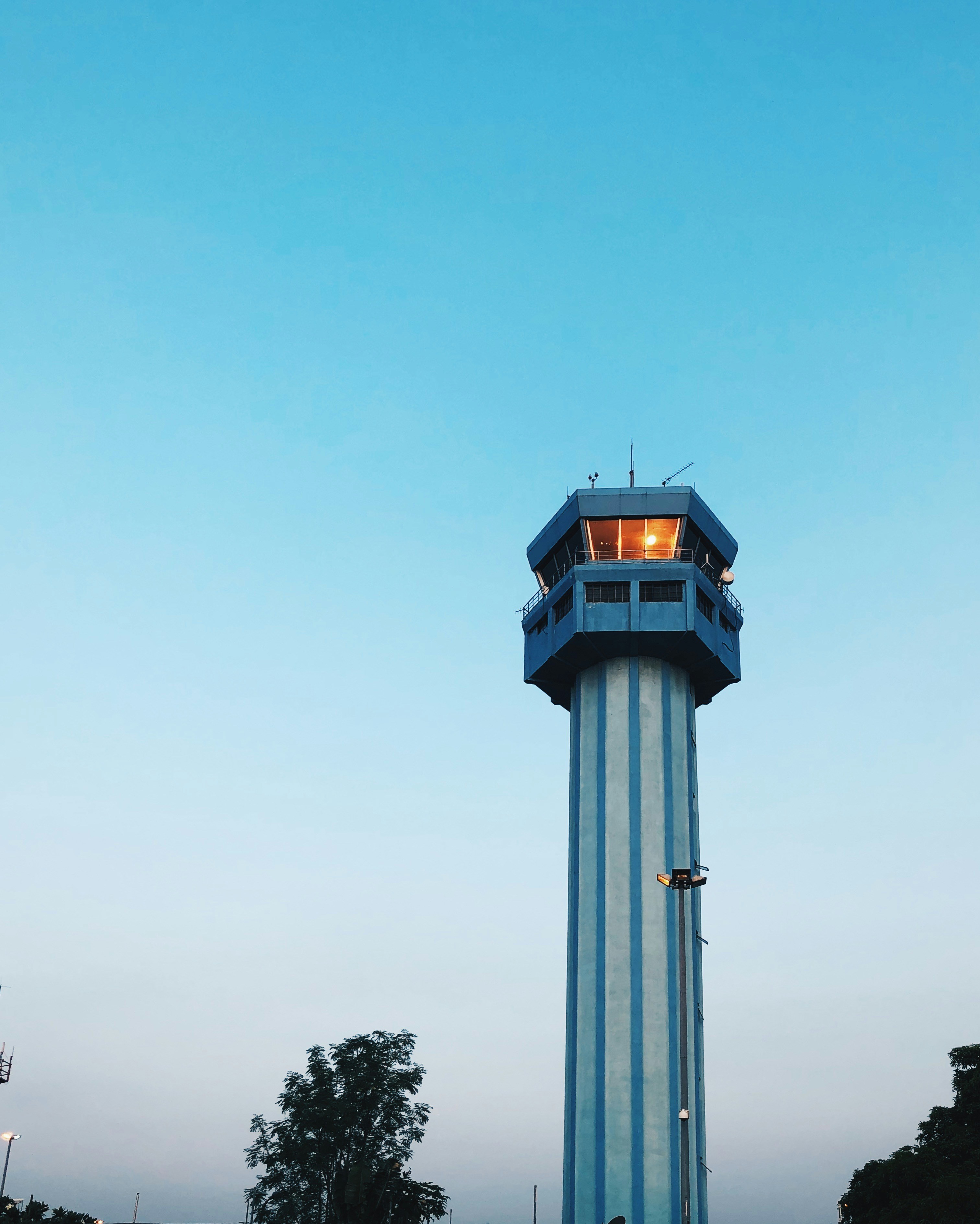 Control tower standing tall against a gradient sky, illuminated at dusk. The structure showcases a blend of functionality and architectural design.