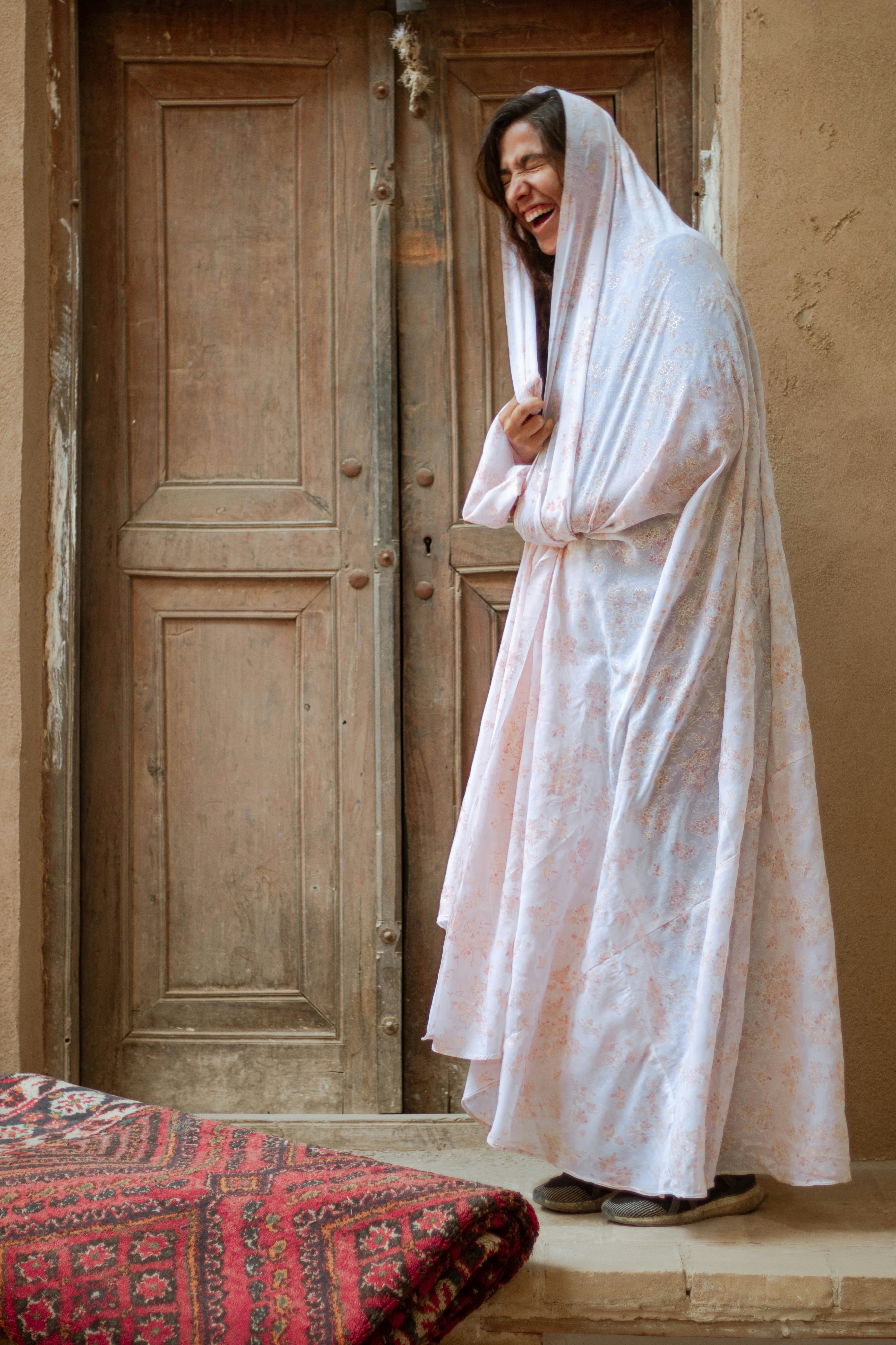 Woman in white robe standing near brown wooden door photo – Free Yazd ...