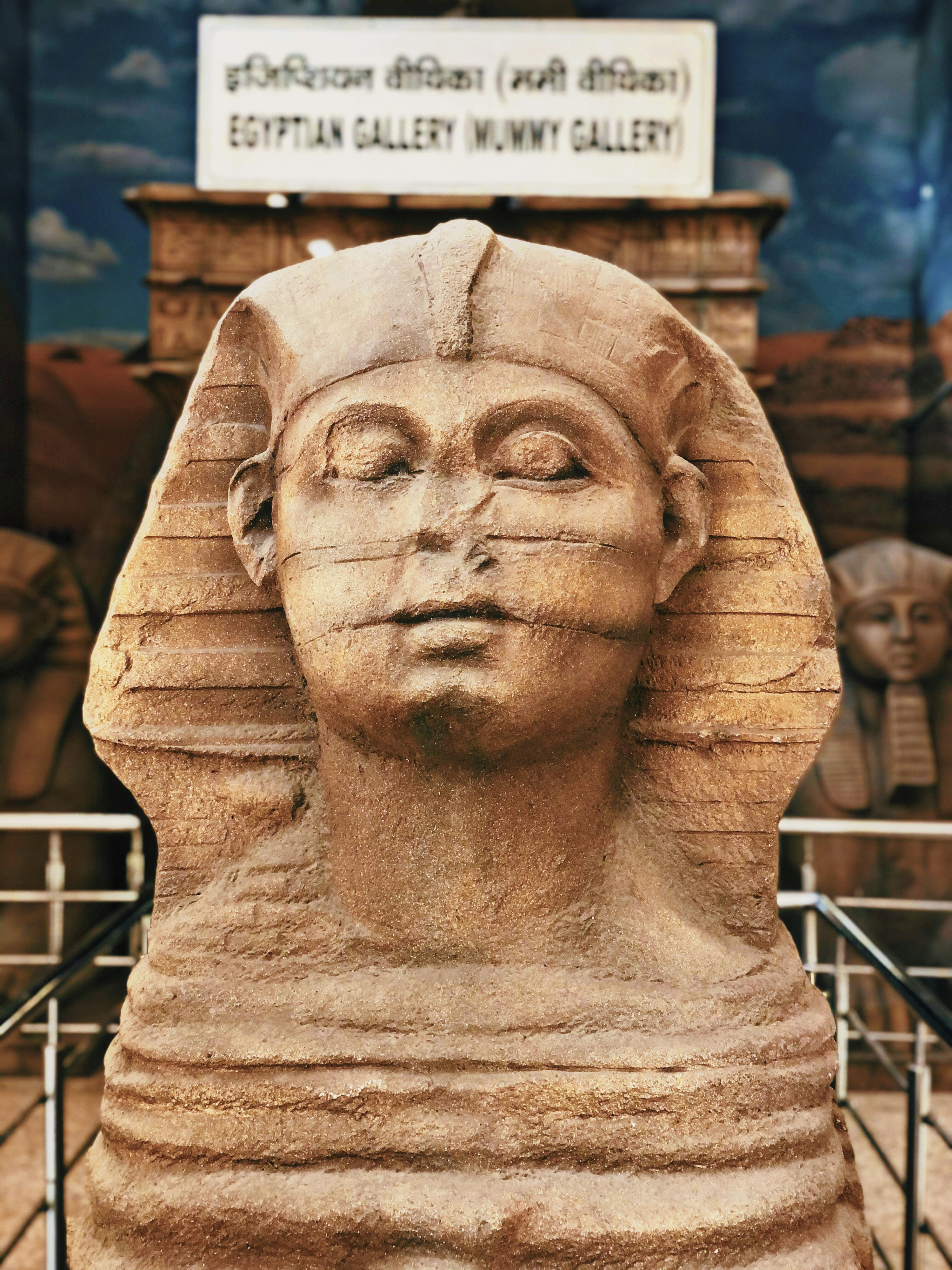A detailed sculpture of a pharaoh, prominently displayed in the Egyptian Gallery, surrounded by other historical artifacts. The artwork showcases intricate carvings and a serene expression.