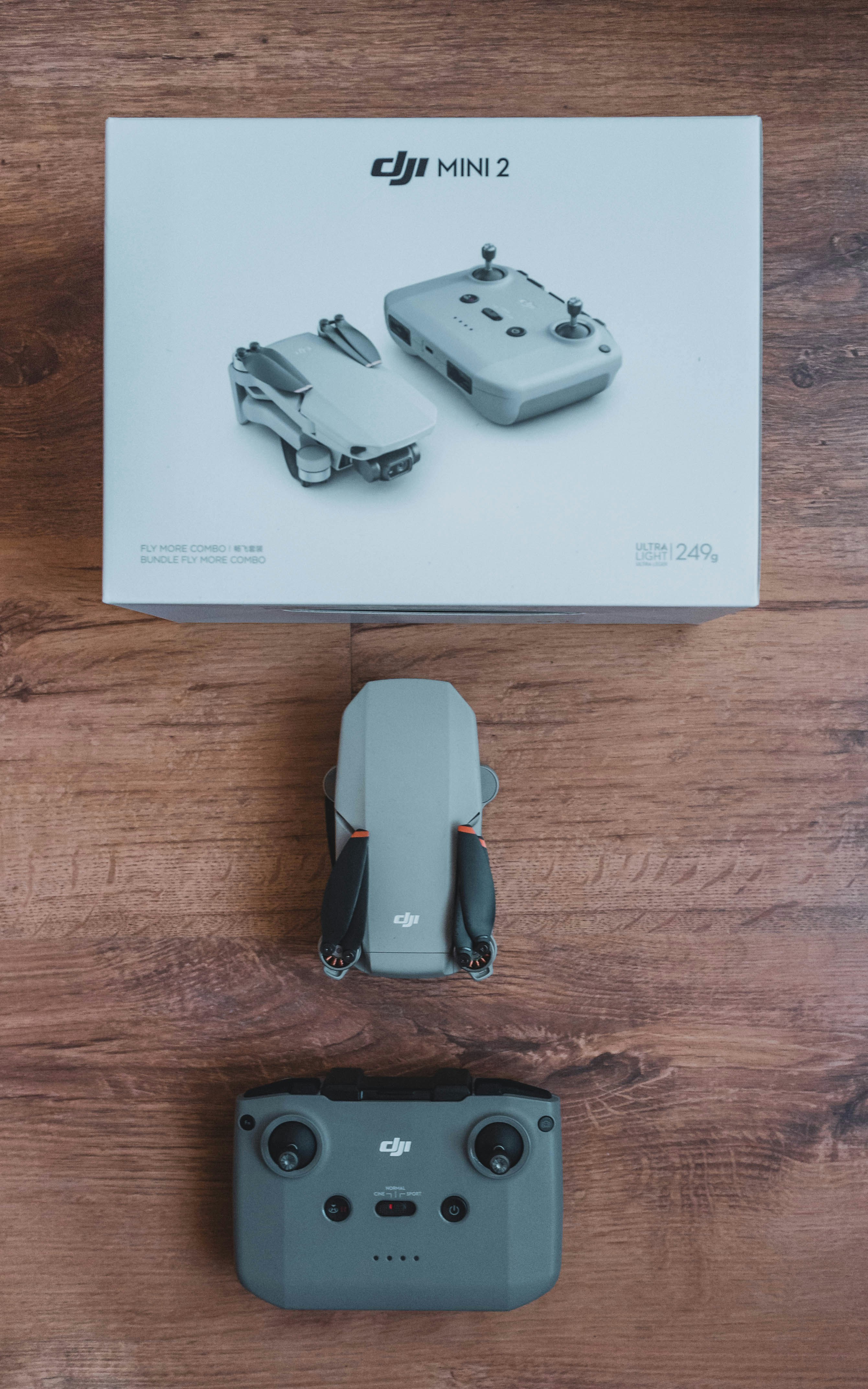 Compact Flight Kit on a Wooden Stage: DJI Mini 2 Box, Foldable Drone, and Controller