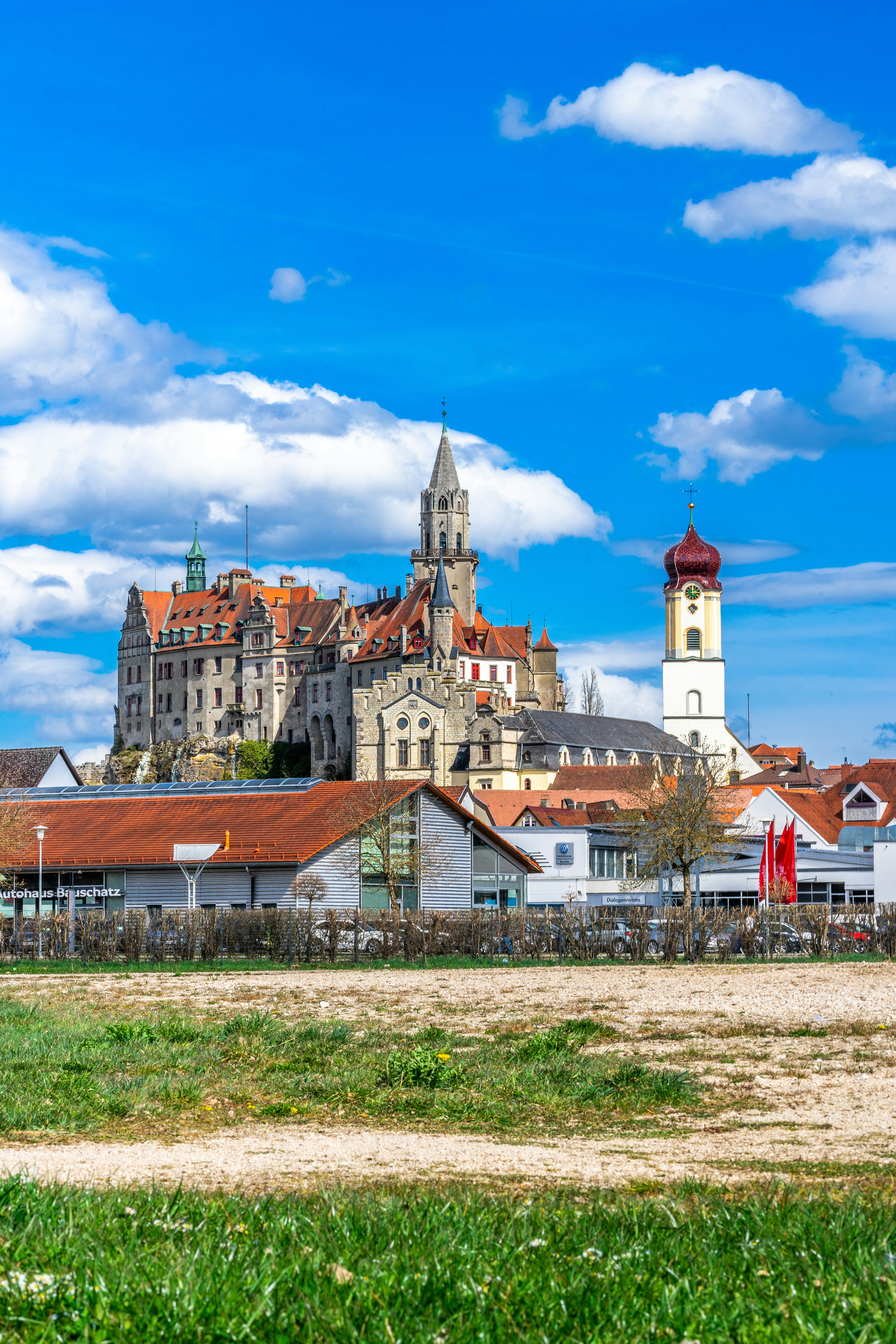 Bell Tower Rising Over a Red-Tiled European Town Under a Clear Blue Sky