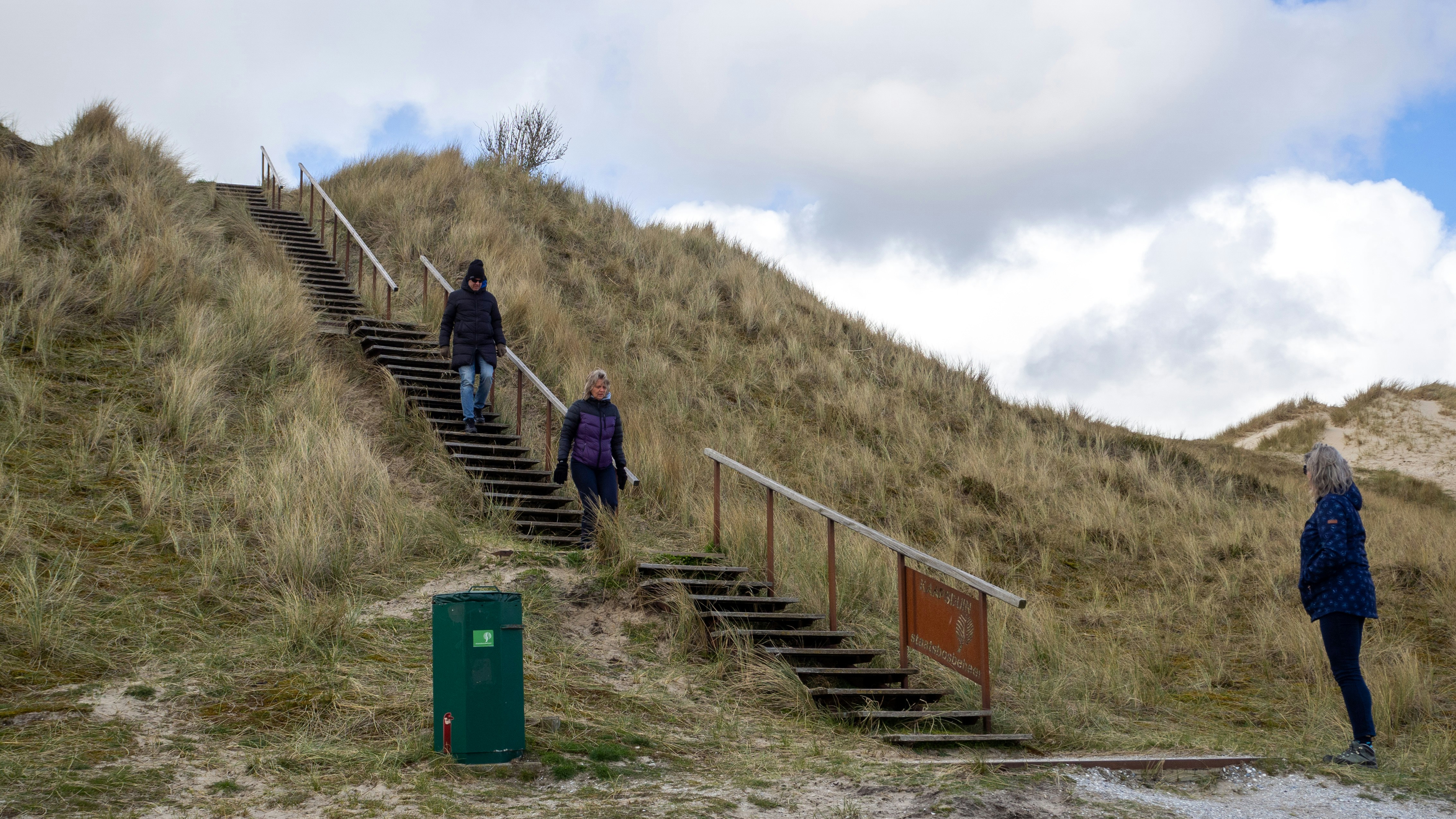 Stairway to Dunes: People Trekking a Wind-Swept Path