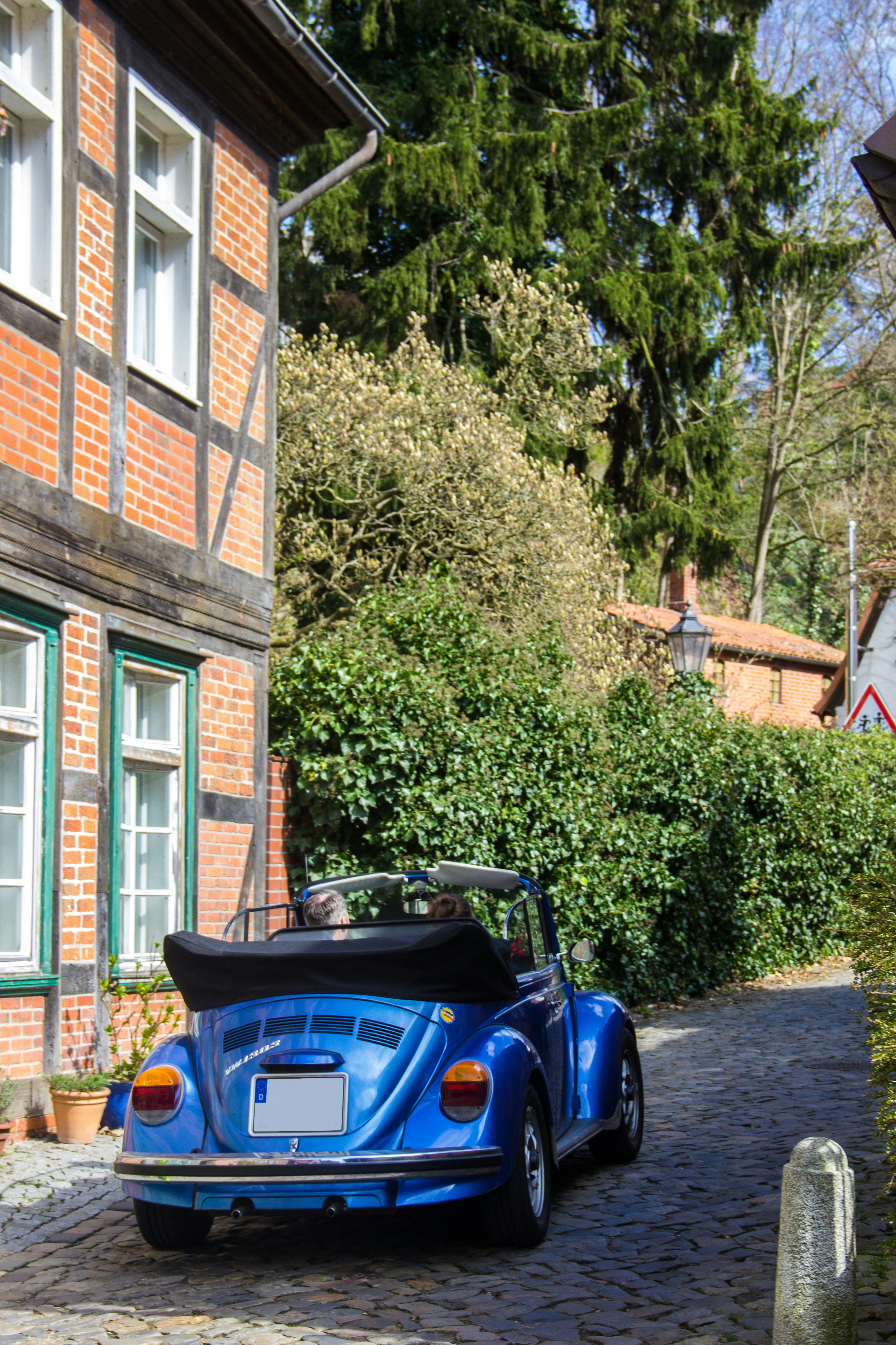 Blue VW Beetle Convertible on a Cobblestone Lane by a Timber-Framed Facade