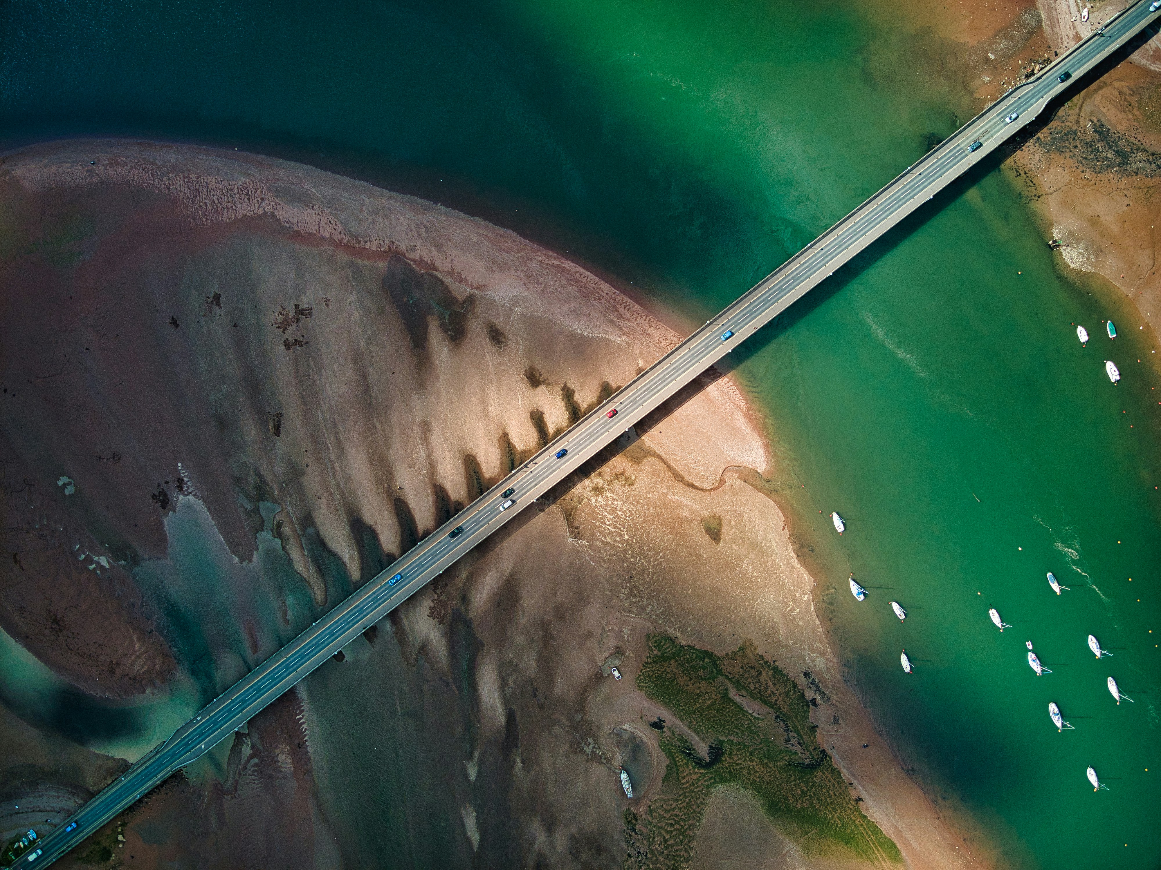 Bridge crossing the teal and brown waters of Teign Estuary with vehicles and boats below.