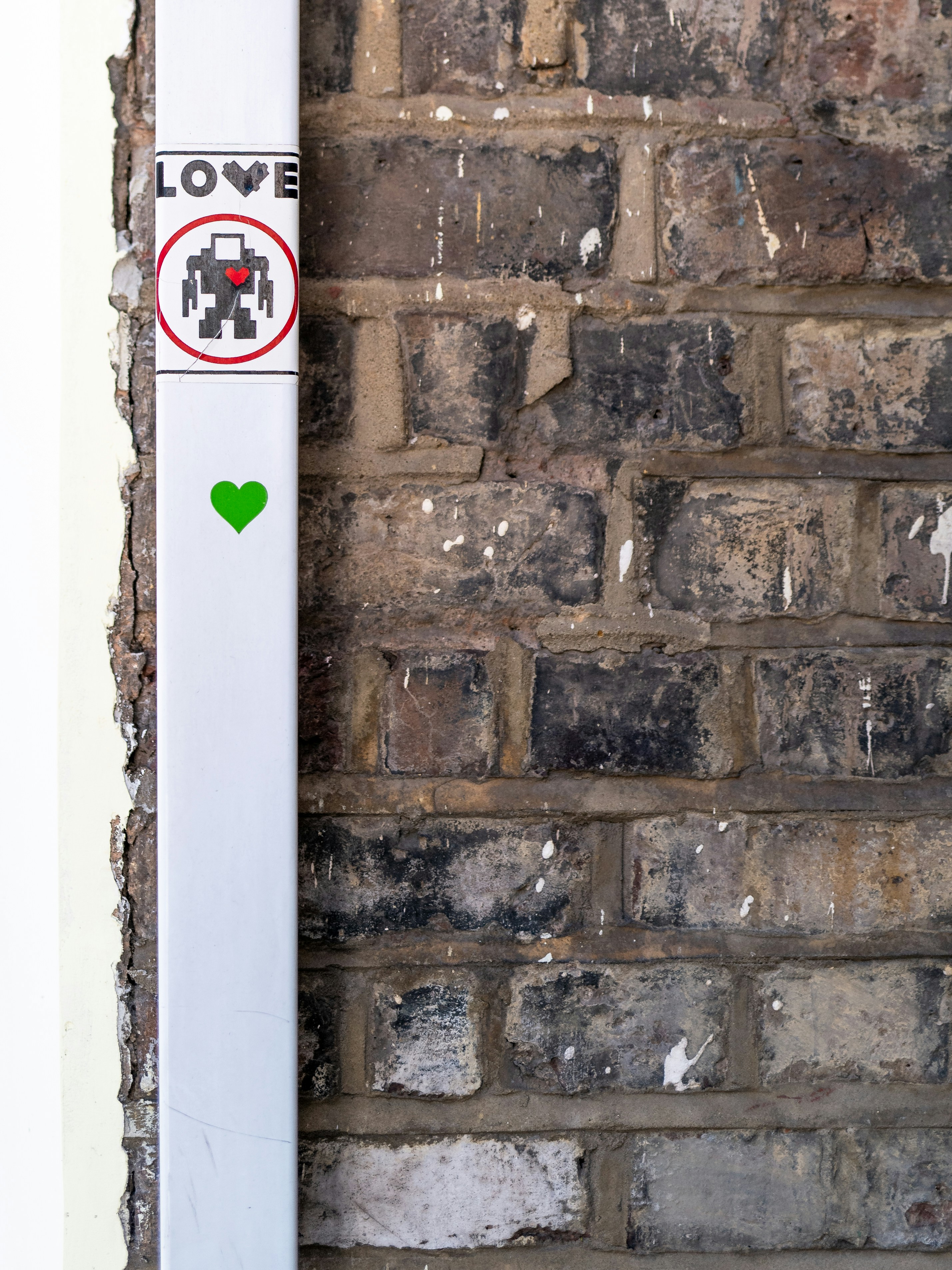 Green Heart on Weathered Brick: Stickered Vertical Strip in Urban Light