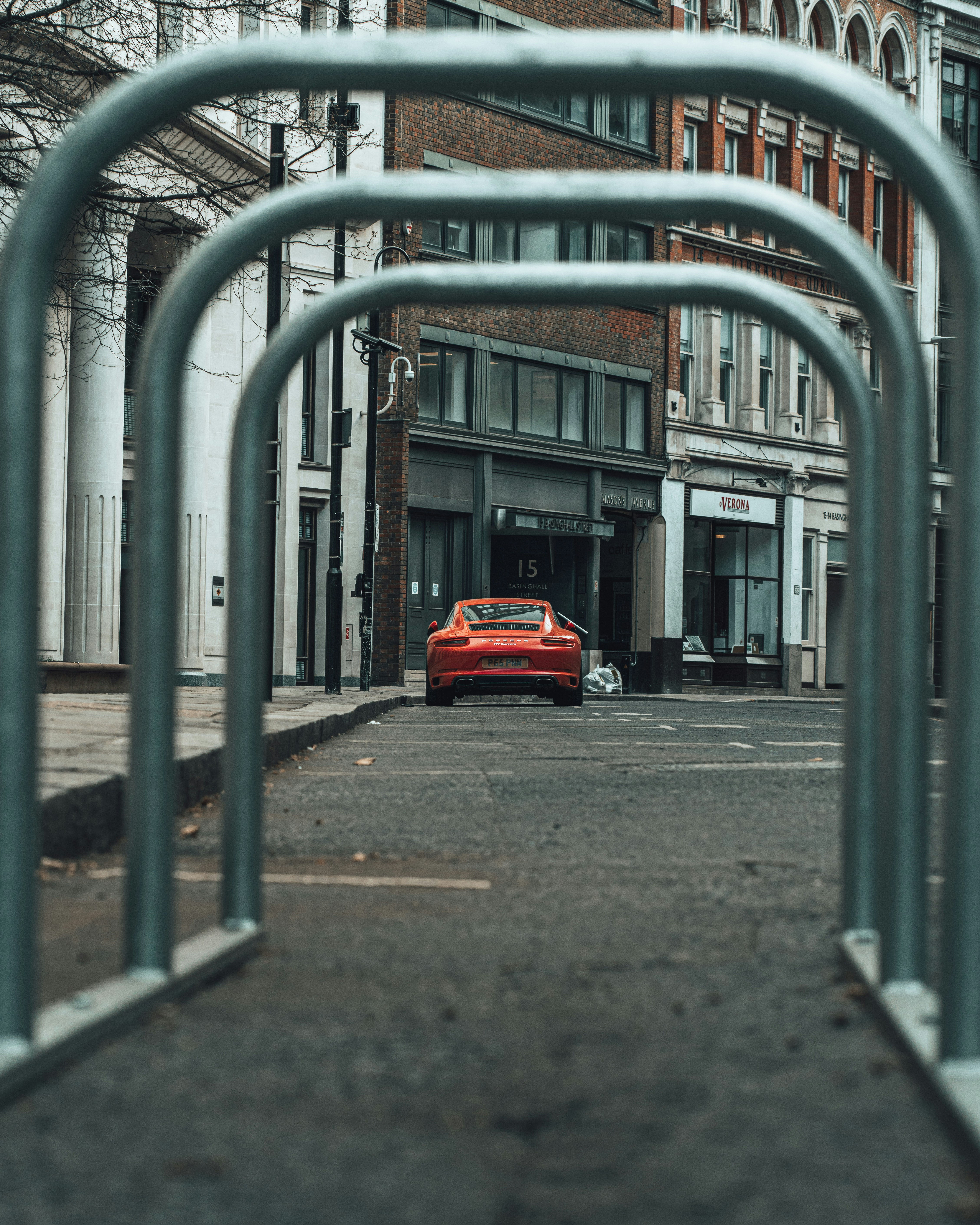Red Car Framed by Repeating Rails on a Quiet City Street