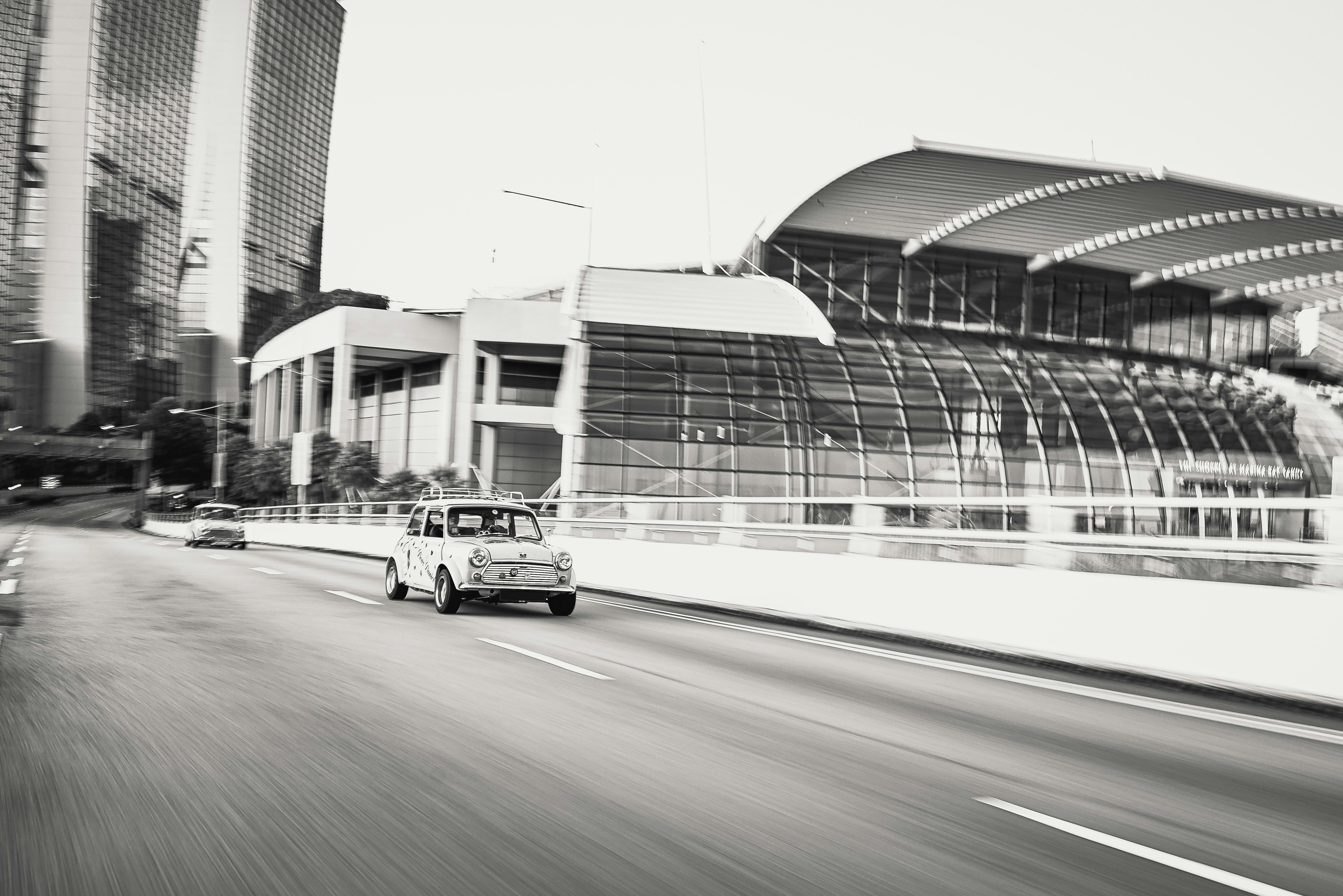 Motion in Mono: A Vintage Car Slides Across a Modern Bridge