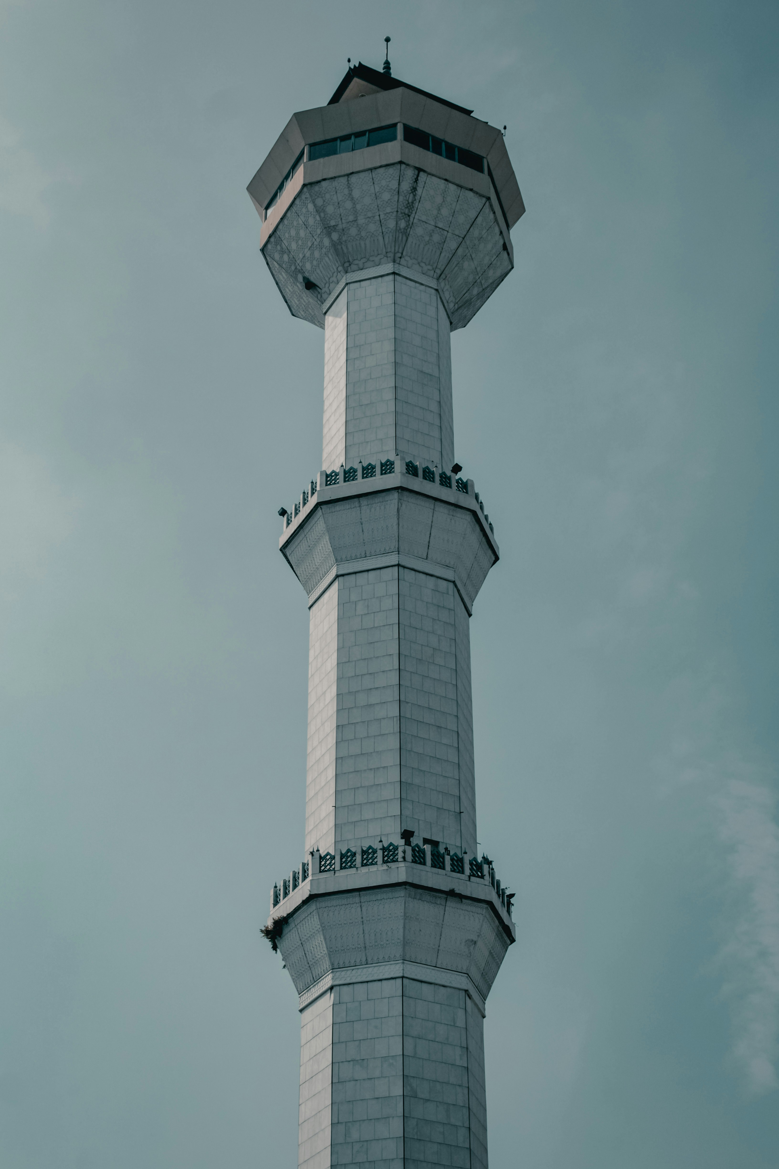 A towering structure rises against a muted sky, showcasing modern architectural lines and intricate details. The design emphasizes verticality and grandeur.