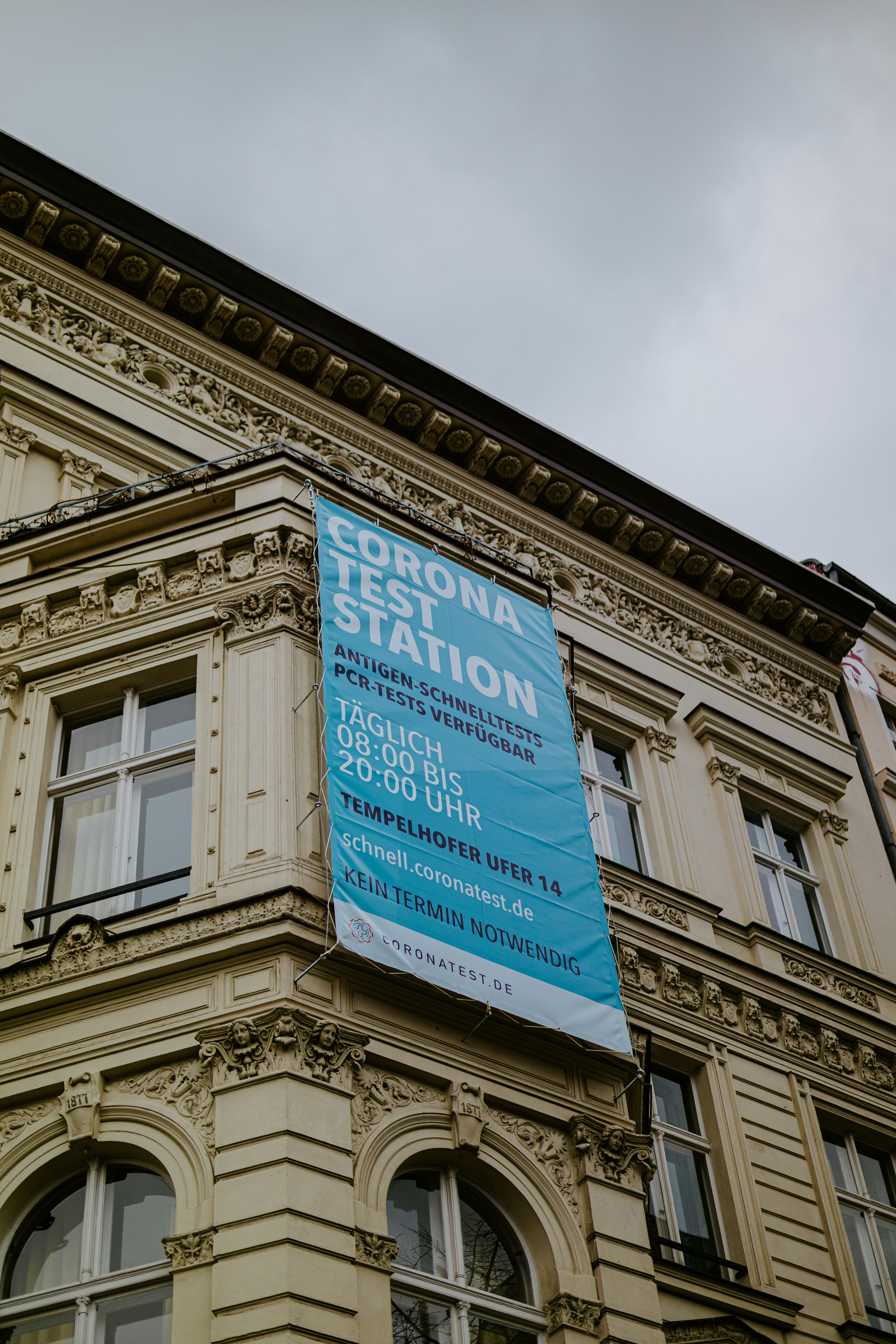 Blue Corona Test Banner Adorns a Timeworn European Facade