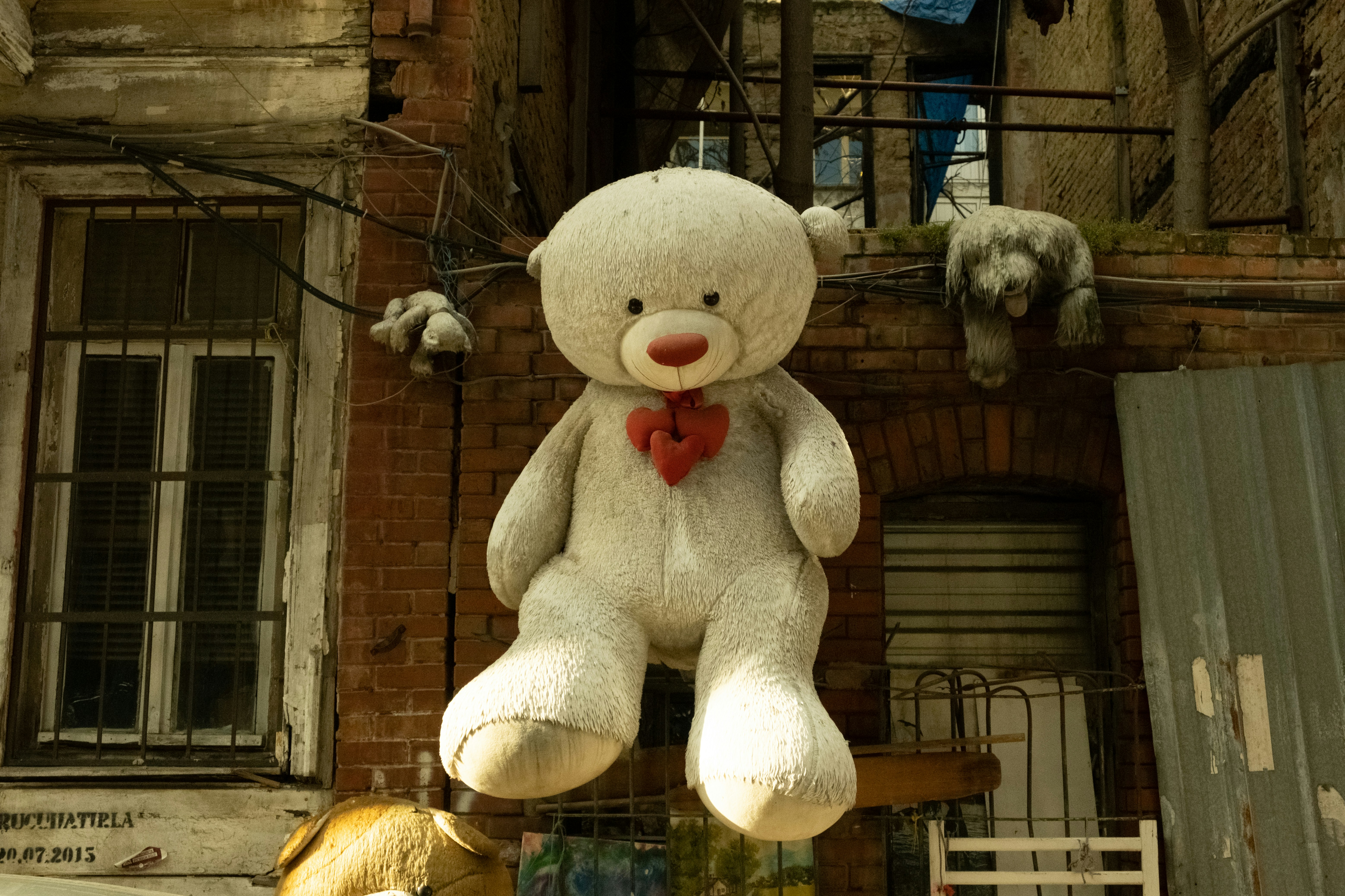 Oversized Teddy Over a Weathered Urban Facade