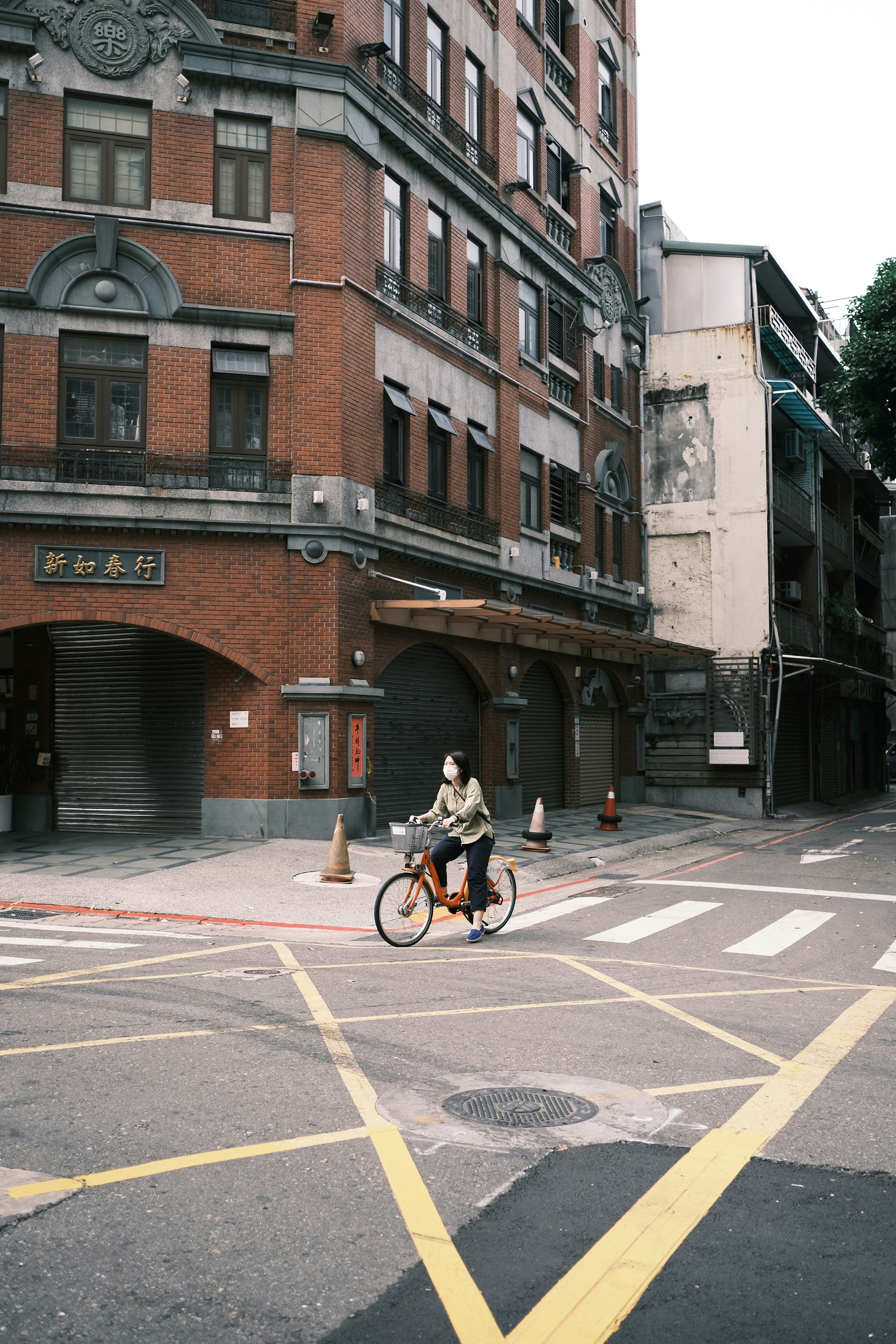 Crosswalk Cadence: A Solitary Cyclist Beneath Brick Facades
