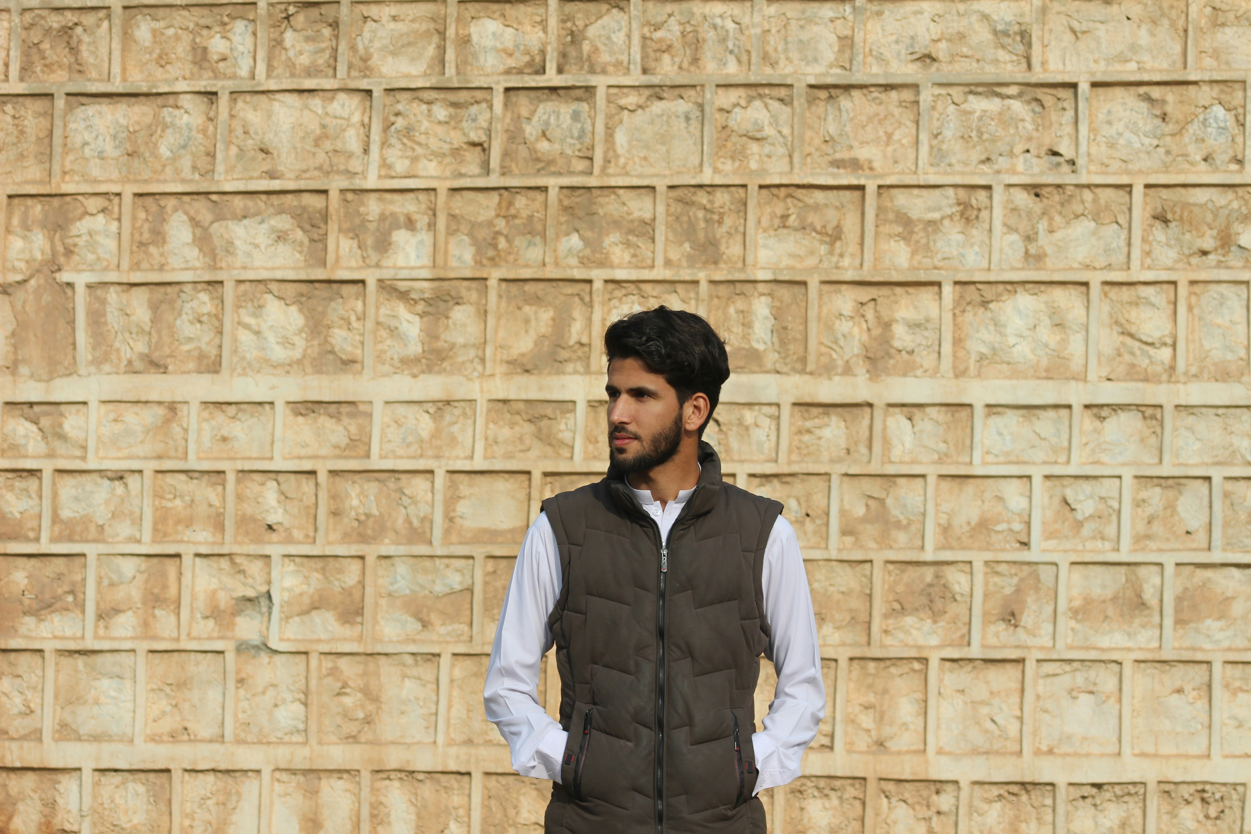 Brick-Walled Contemplation: A Man in a Puffer Vest