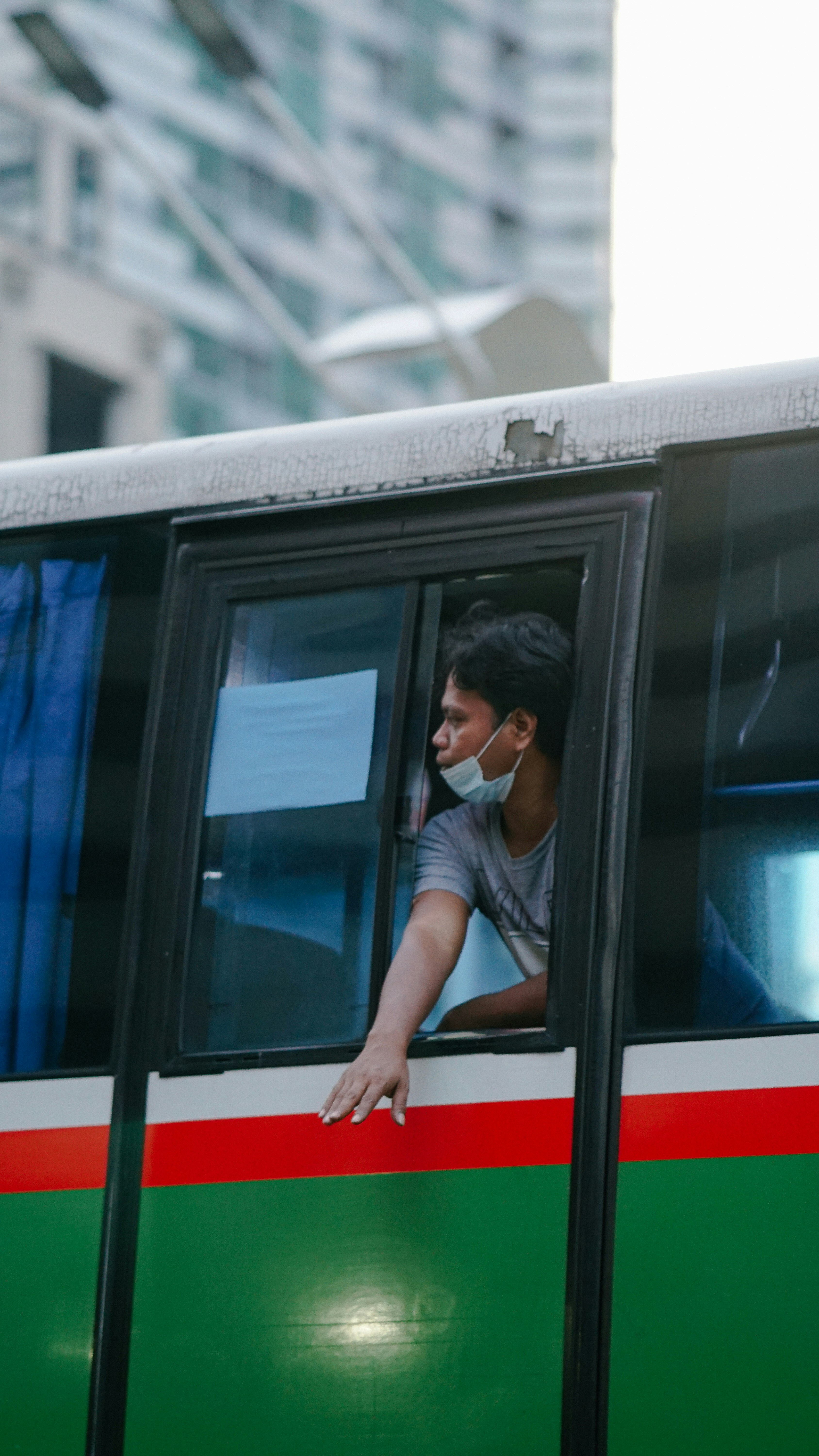 Peering Through the City Bus Window: A Masked Commuter in Transit