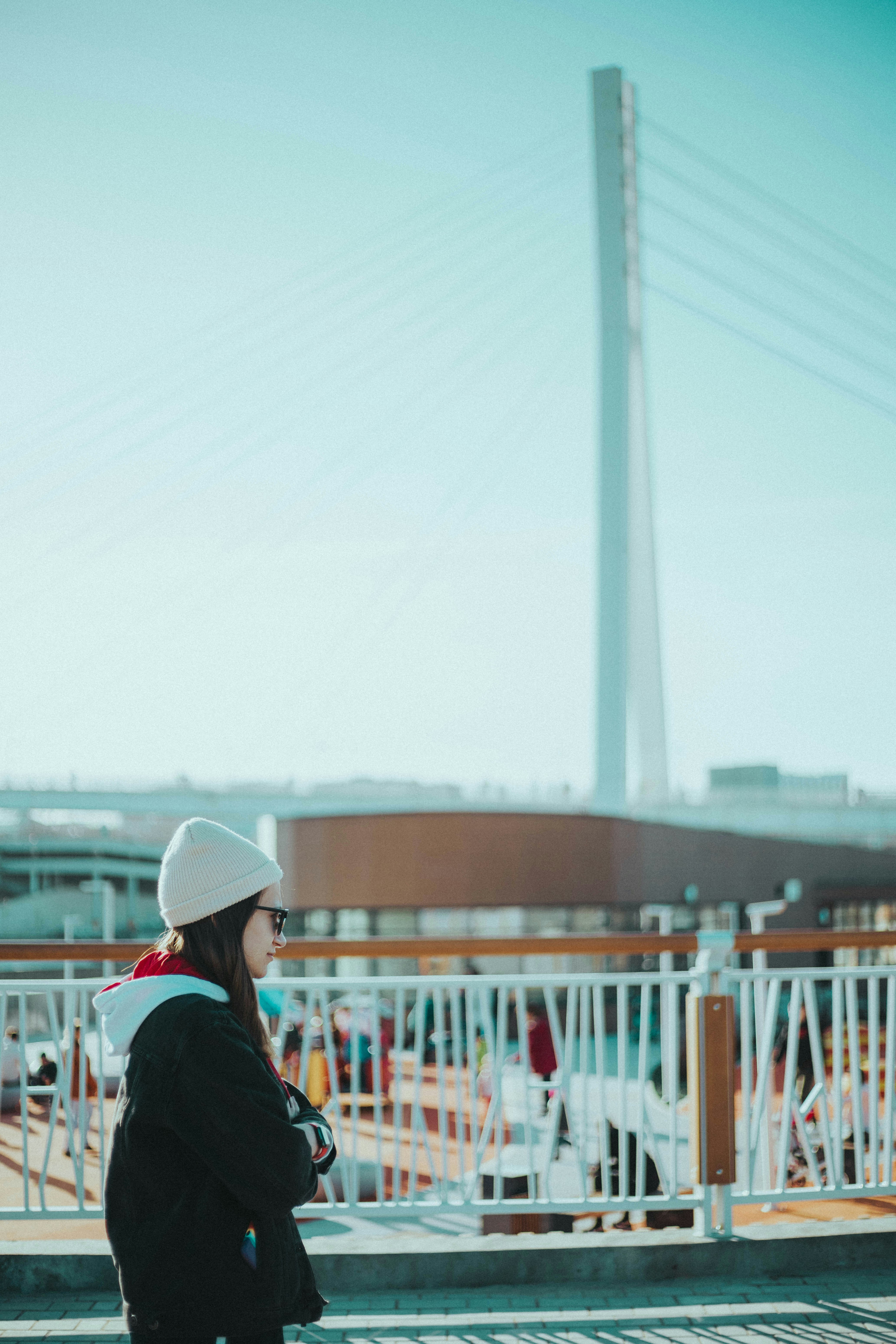 man in black jacket and white cap standing near white metal fence during daytime