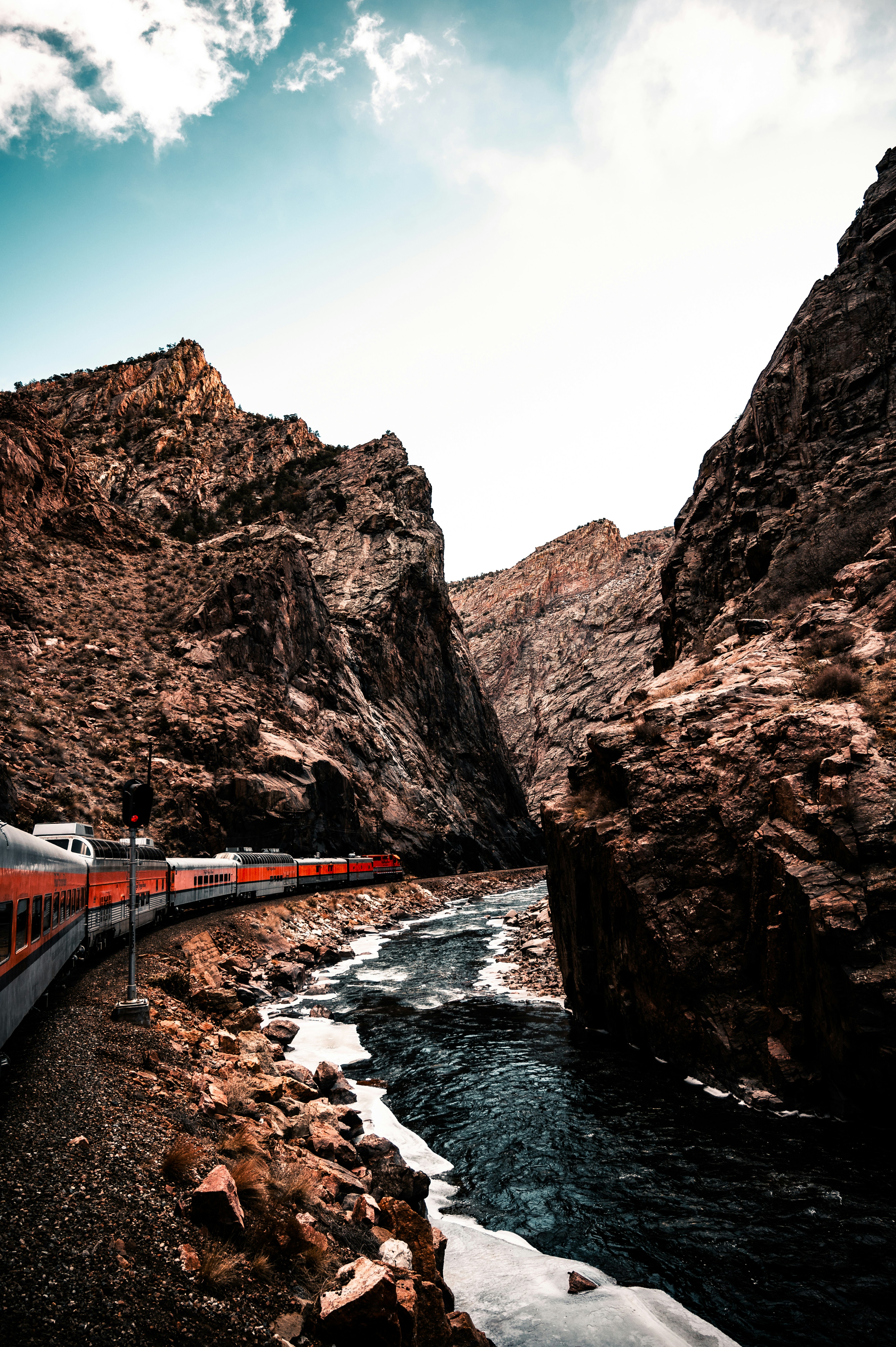 Railway Through the Gorge: A Red-Train Wake in Rugged Light