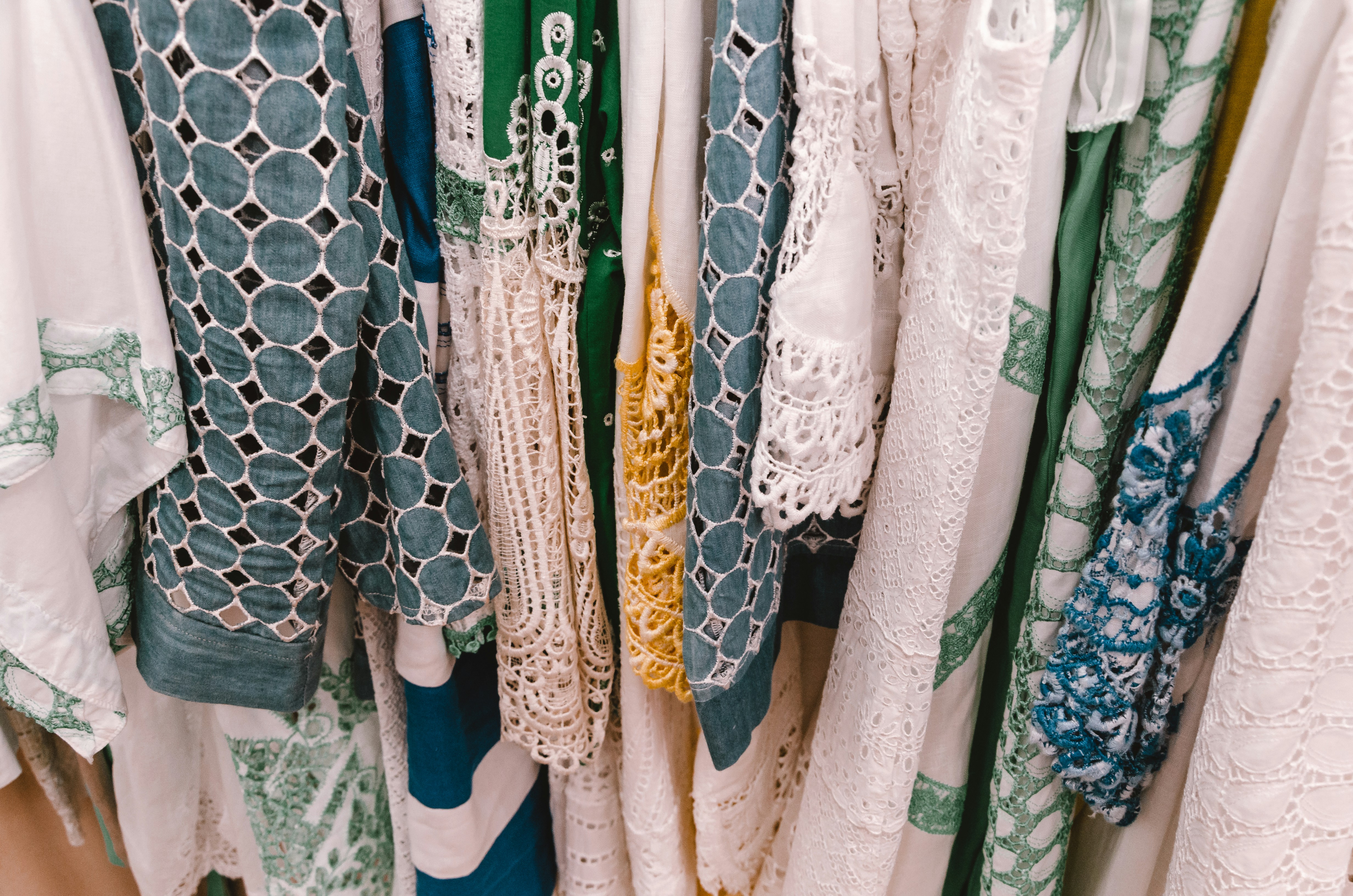 A vibrant collection of intricately designed garments showcasing various fabrics and lace patterns. The assortment features a blend of colors and textures that highlight textile artistry.