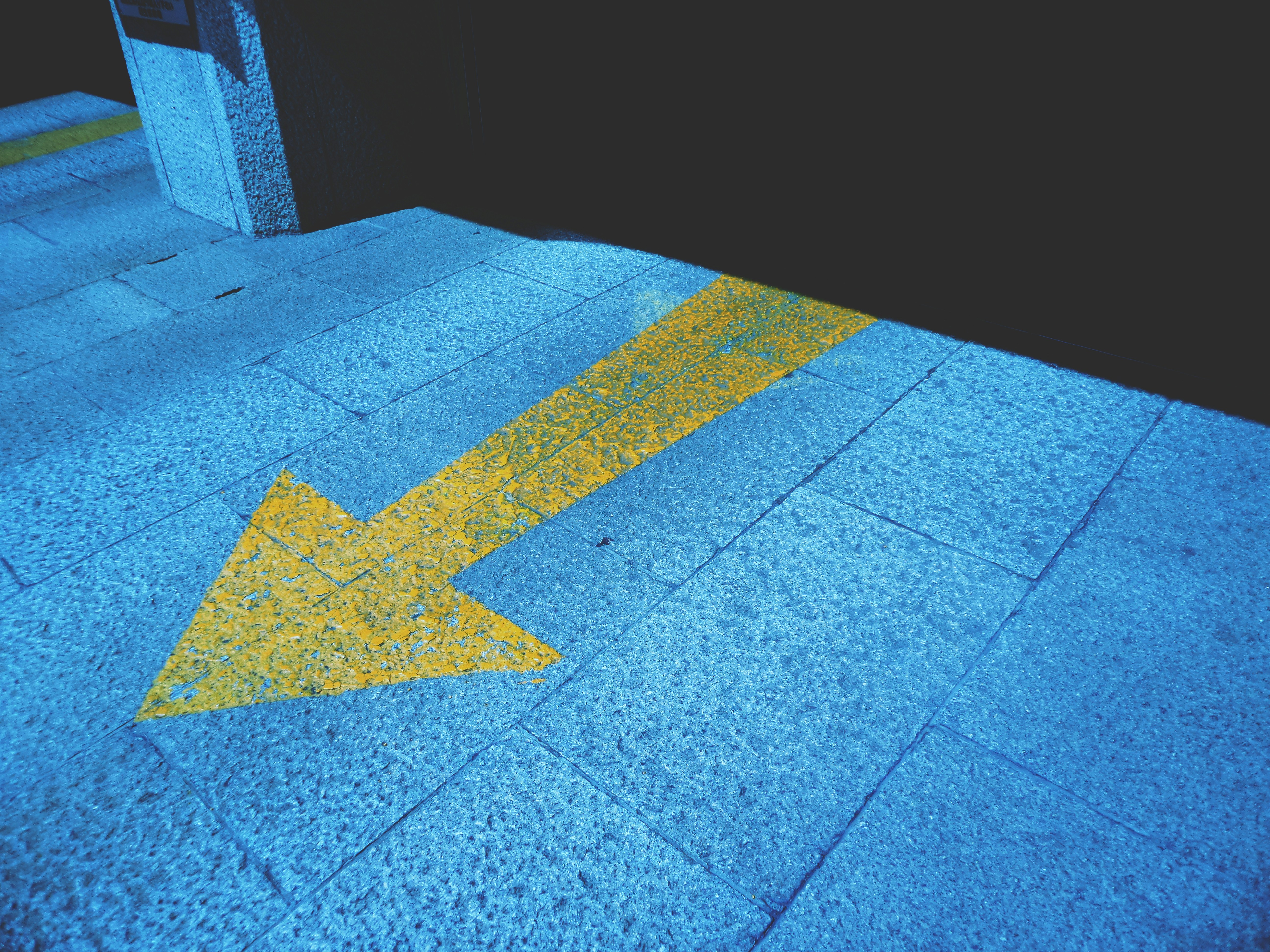 Blue-lit plaza with a bold yellow arrow marking the path