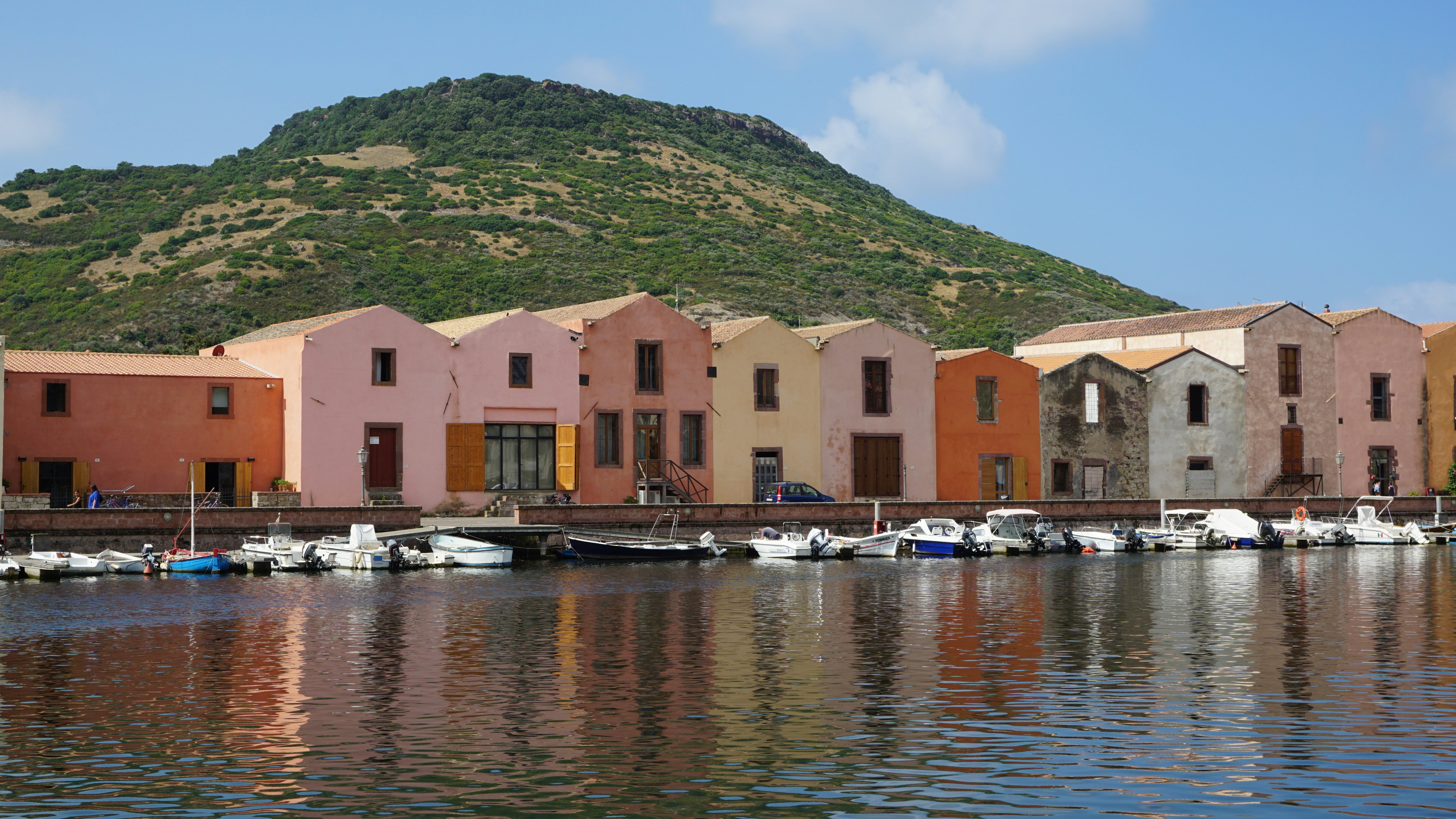 Colorful buildings lining a tranquil harbor, reflecting in the calm water under a bright blue sky.