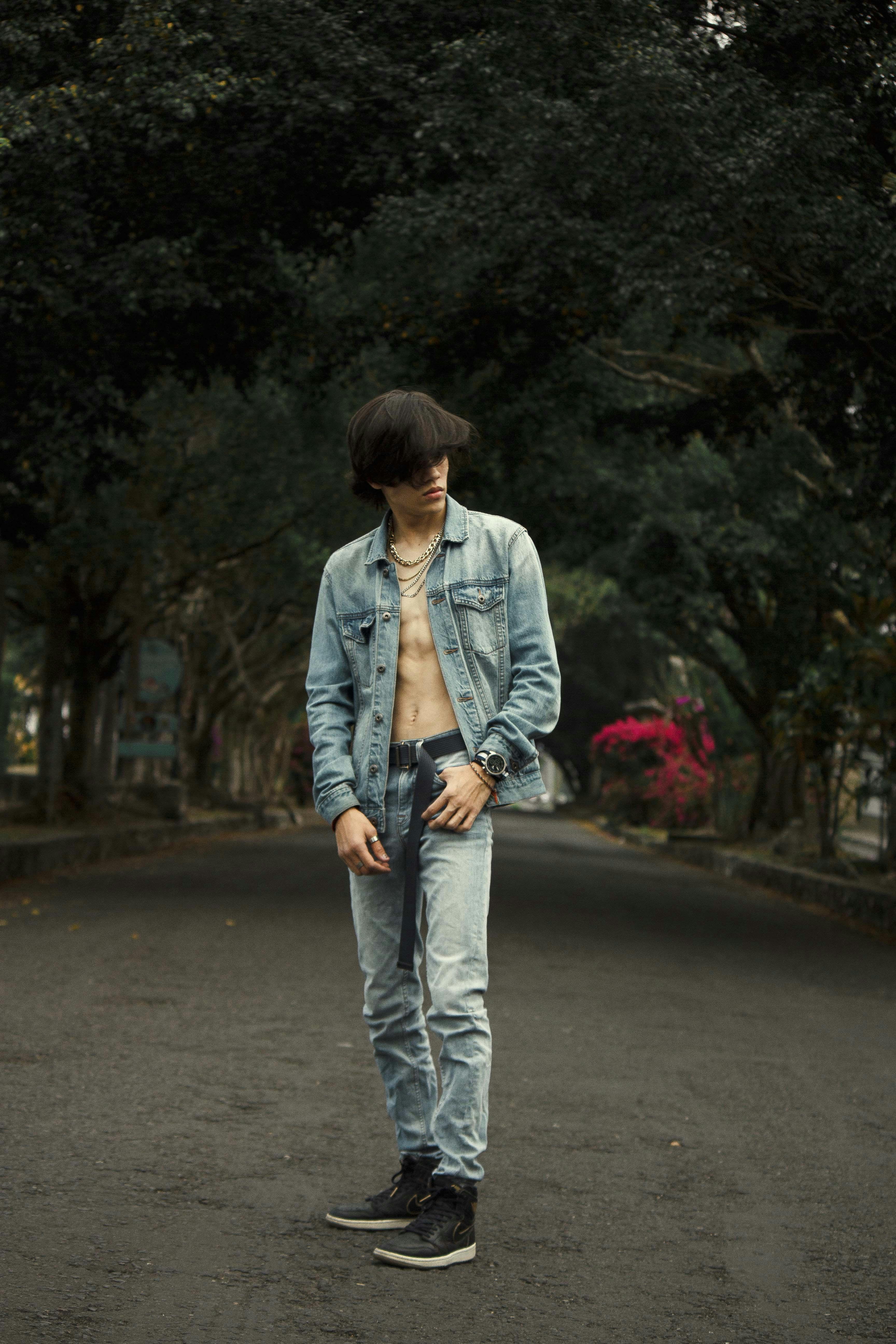 woman in gray denim jacket and blue denim jeans standing on gray concrete road during daytime