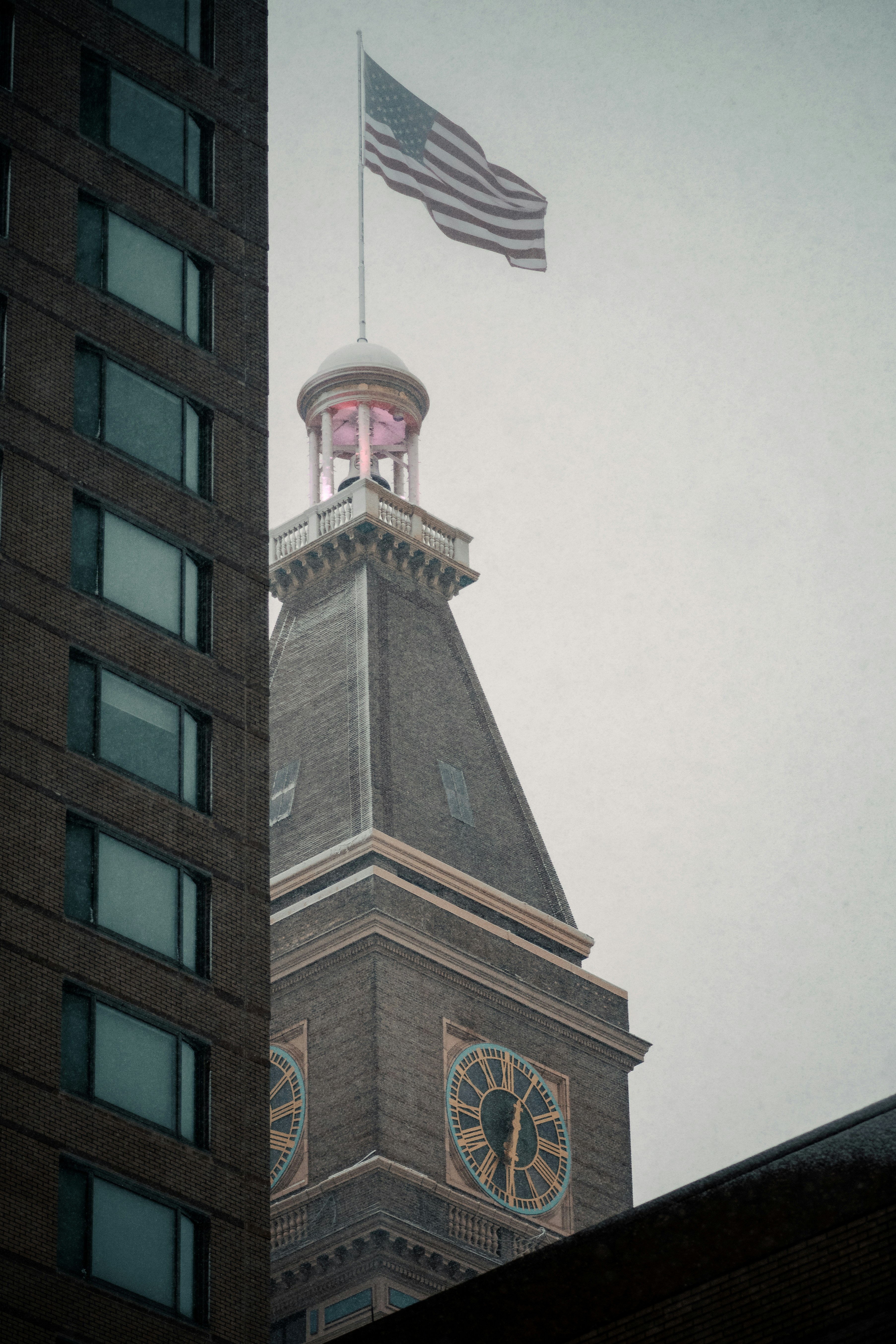 Flag Over the Clock Tower: A Narrow Gap Between Brick, Glass, and Sky