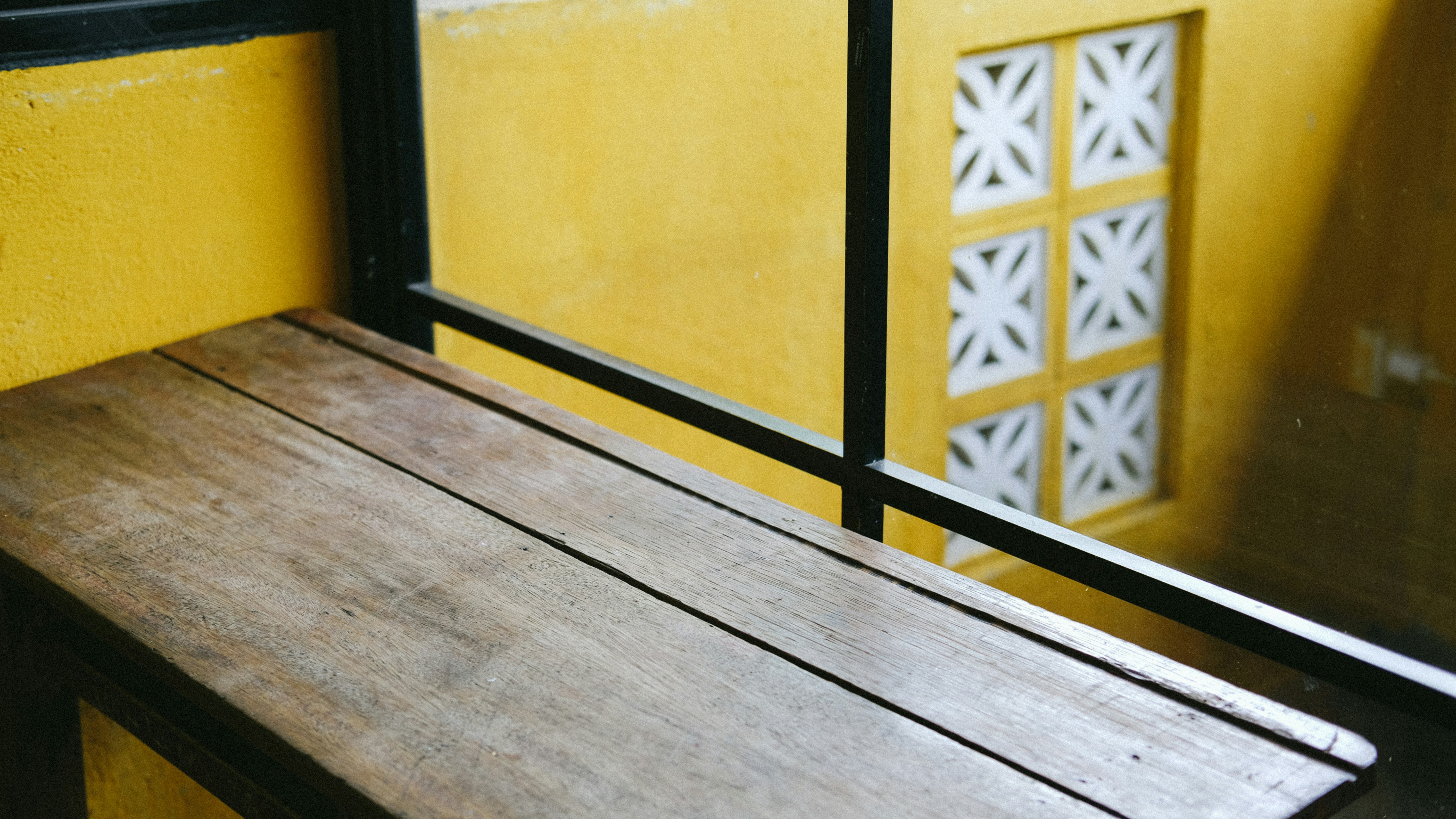 Wooden table set against a vibrant yellow wall, with a glimpse of patterned window behind. The scene exudes a cozy, inviting atmosphere.