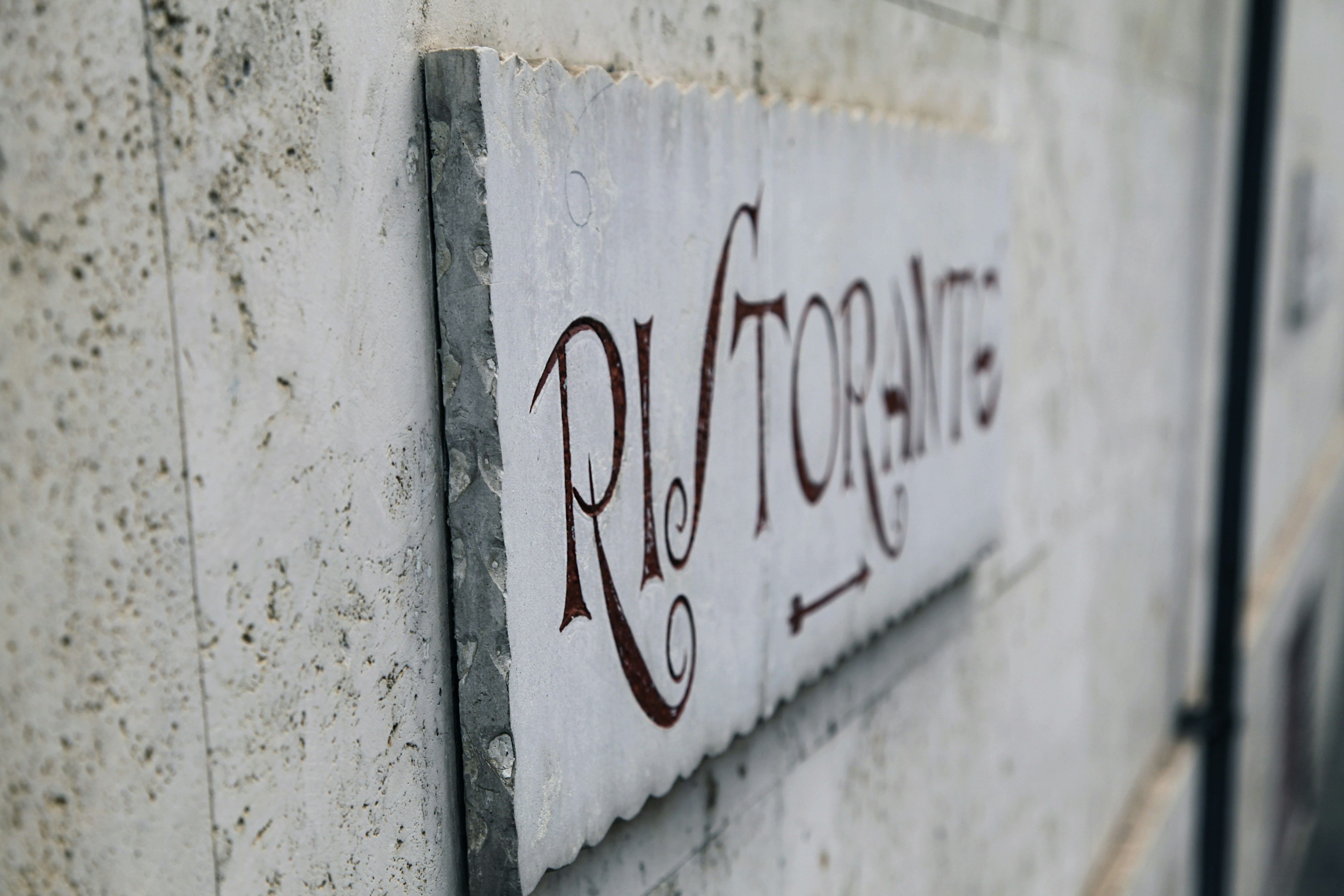 Weathered Plaque with Ornate Typography Clinging to Rough Stone Wall