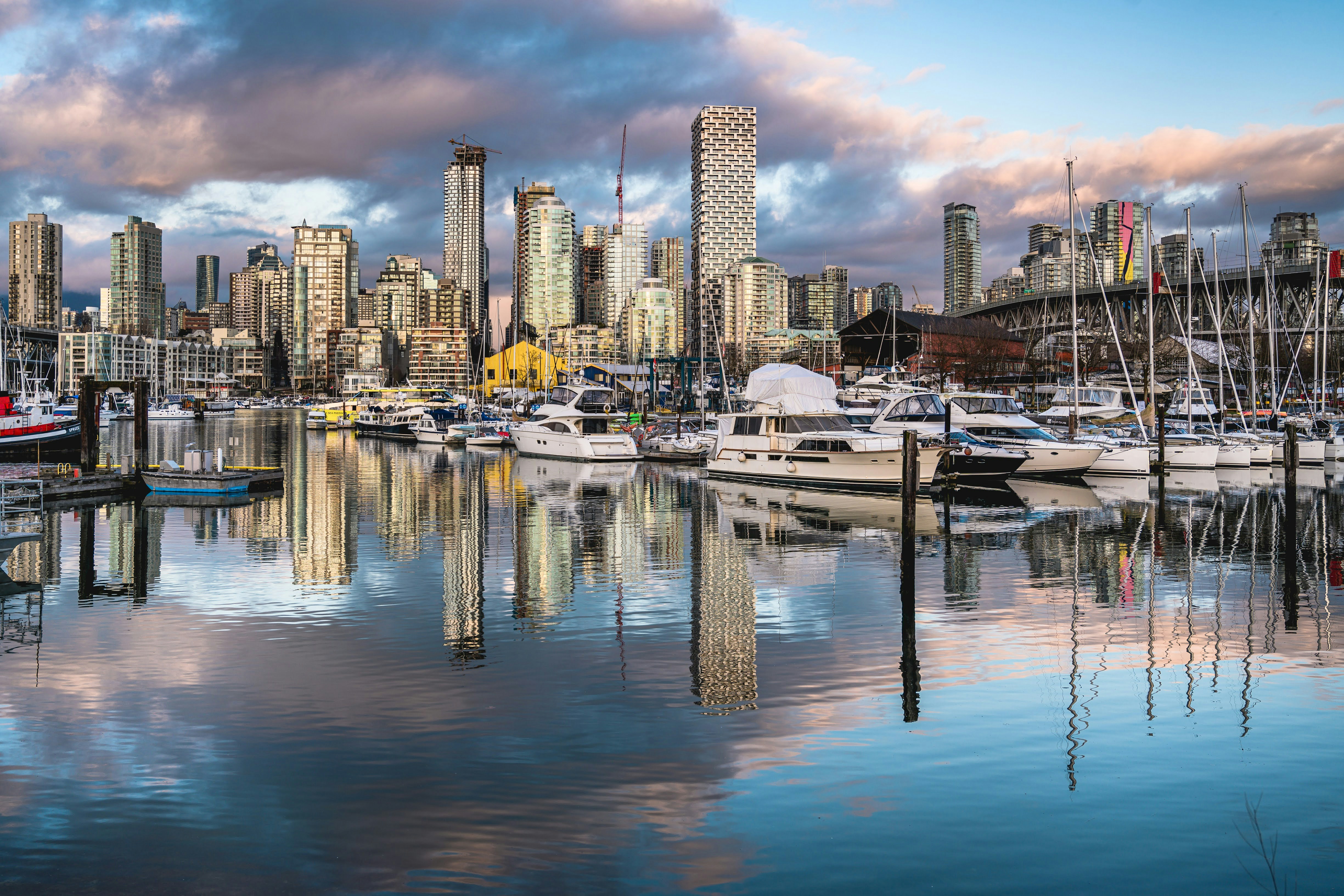 Modern skyline reflected in tranquil marina waters, showcasing boats and city life. The scene captures a blend of nature and urban architecture.