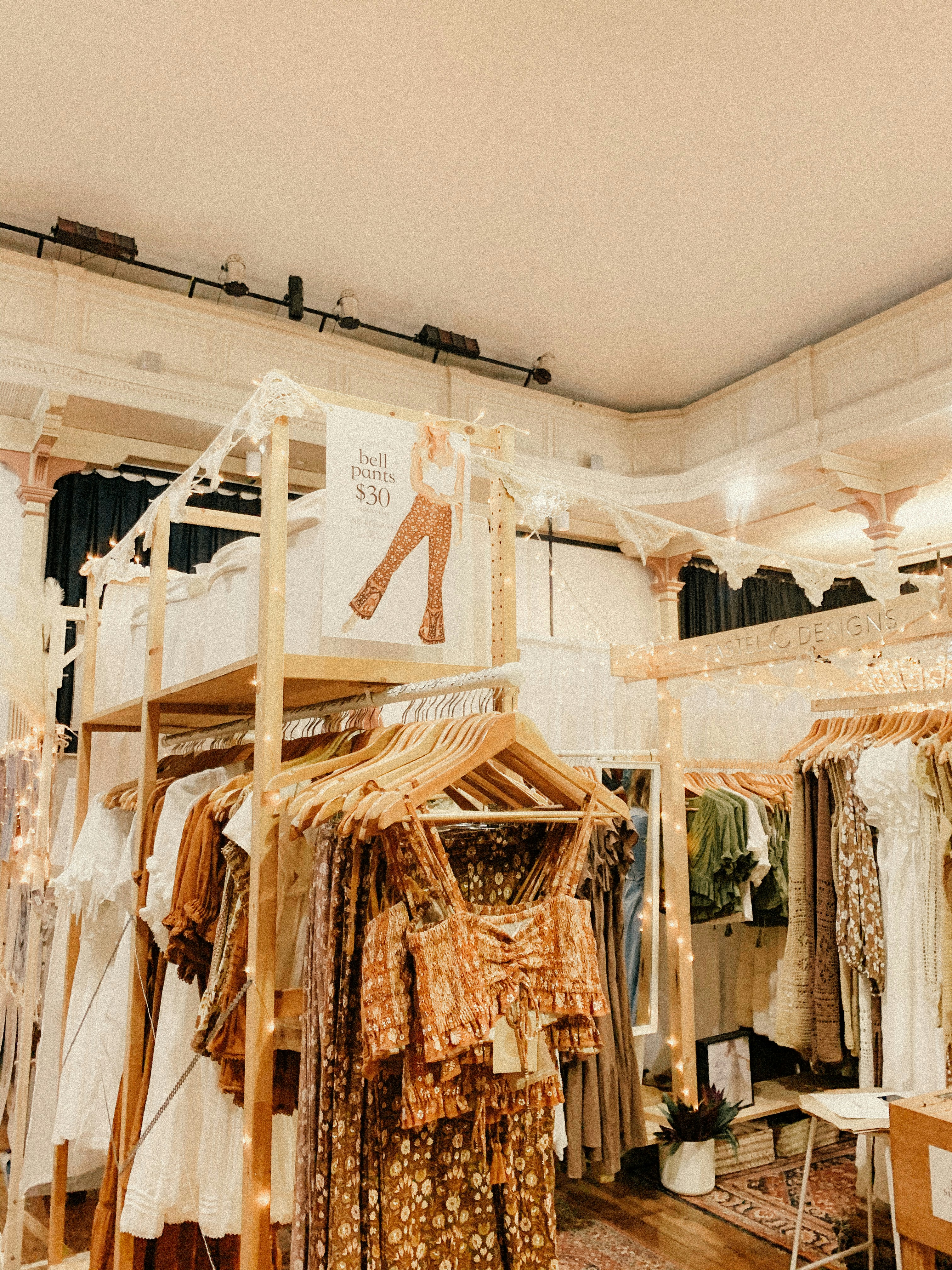 Amber-lit Boutique: Wooden Display and Dressed Racks Under Fairy Lights