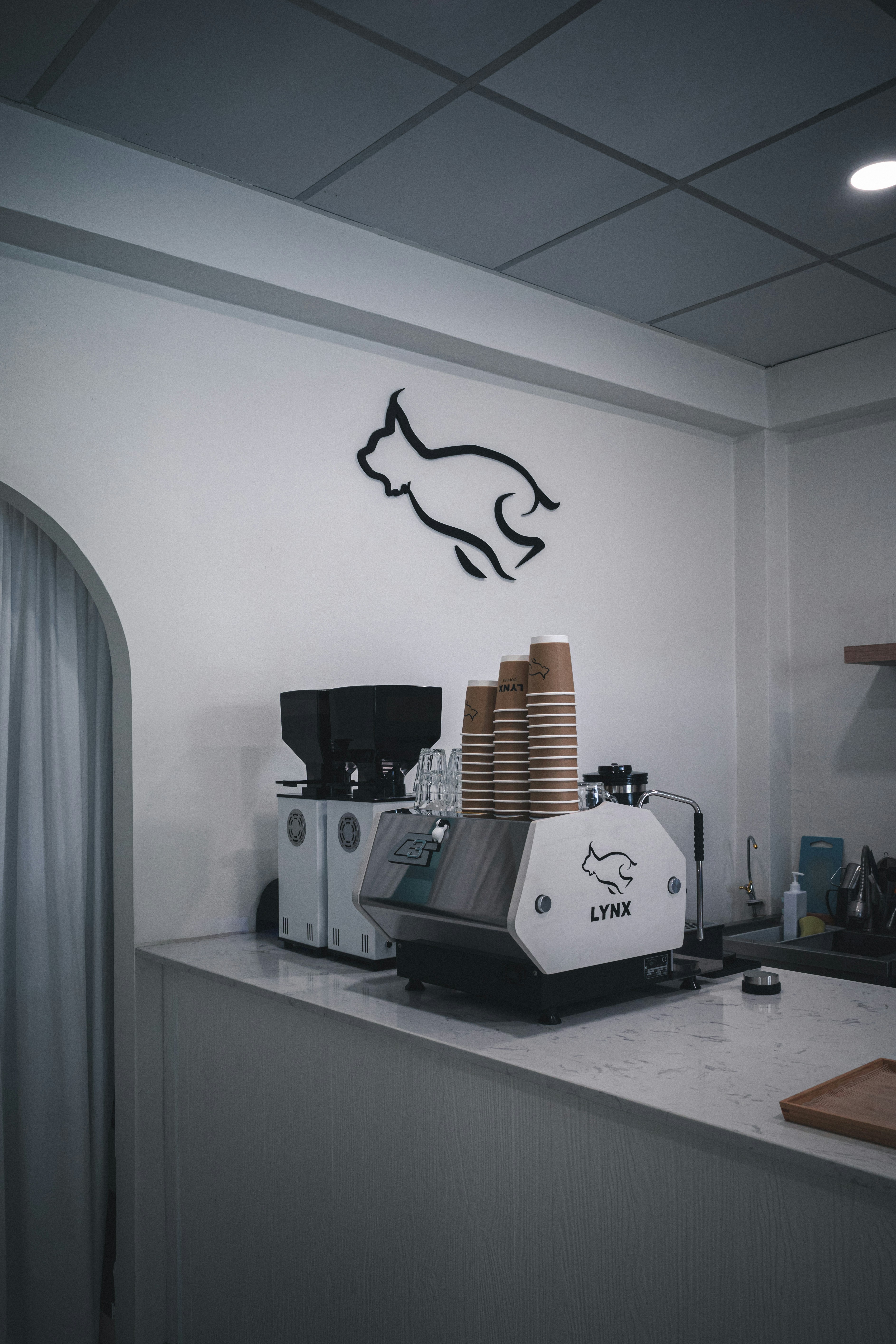 Stylish coffee bar featuring a sleek espresso machine and a playful rabbit logo on the wall. The minimalist design invites a cozy atmosphere.