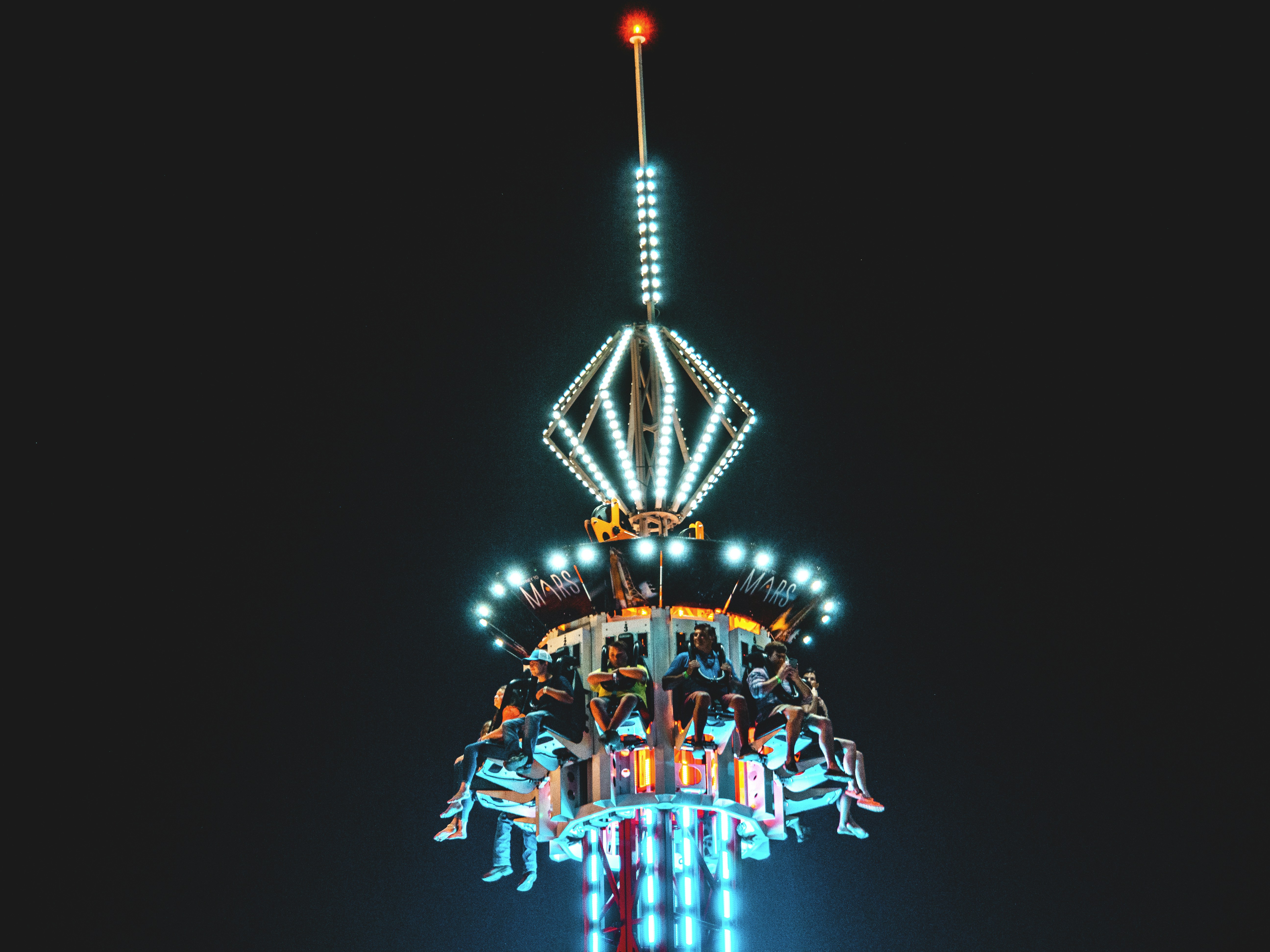 A group of thrill-seekers suspended in mid-air on a brightly lit amusement ride, showcasing the excitement of nighttime entertainment.