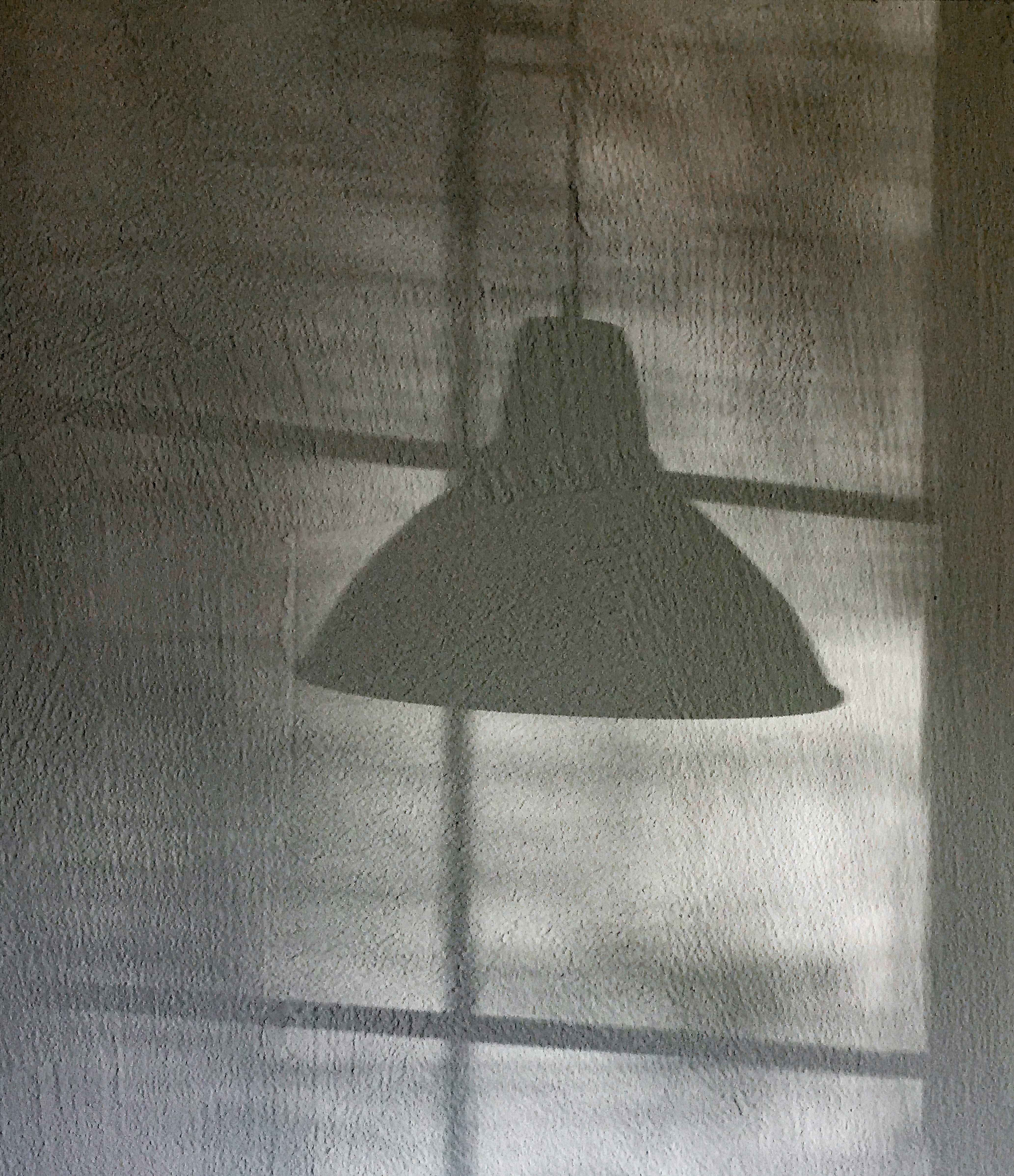 A pendant lamp casts a soft shadow against a textured wall, creating an interplay of light and shadow. The scene evokes a sense of calm and simplicity.