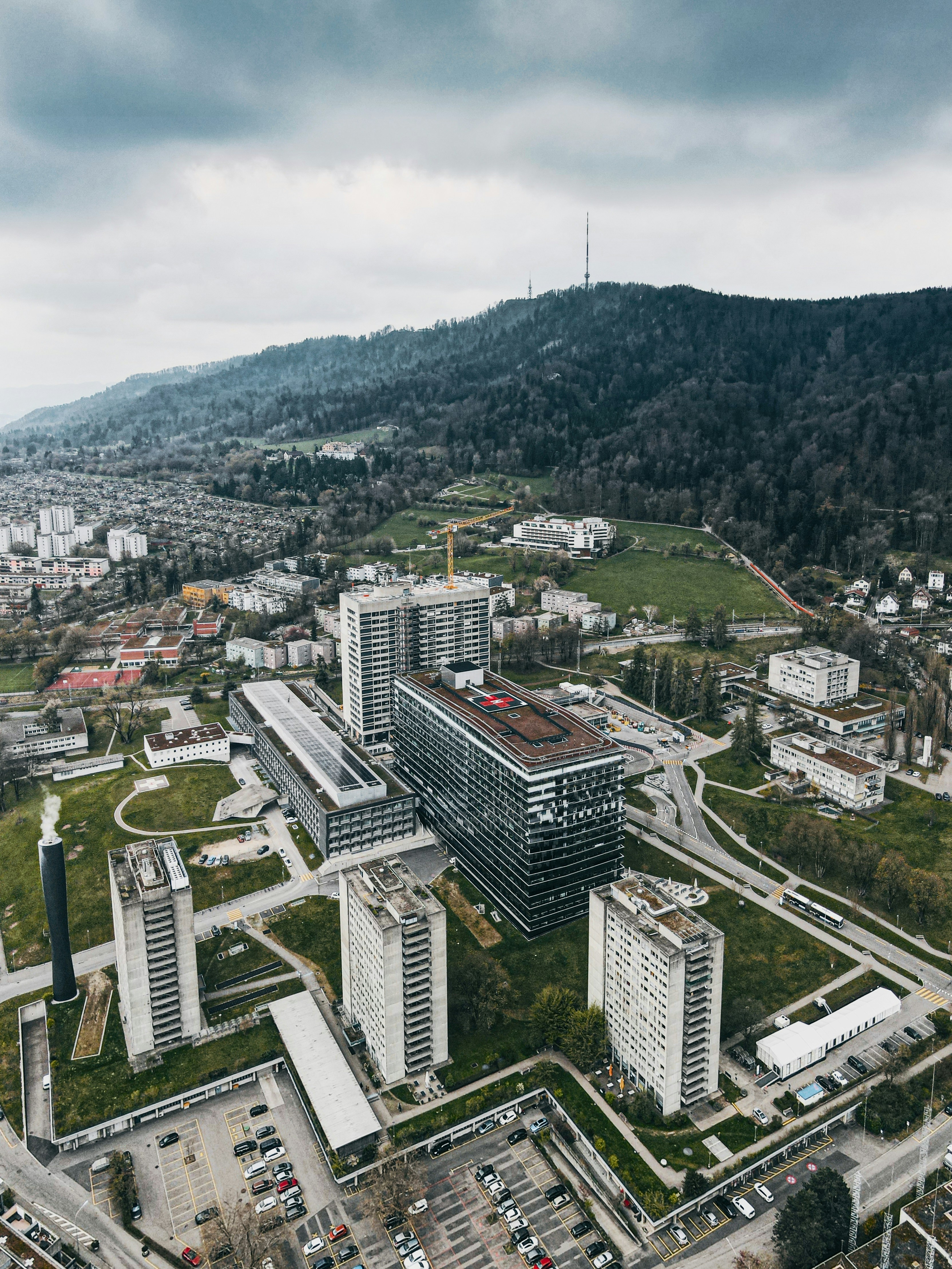 Crane-Lined Campus Towers Rising Under a Misty Hillscape