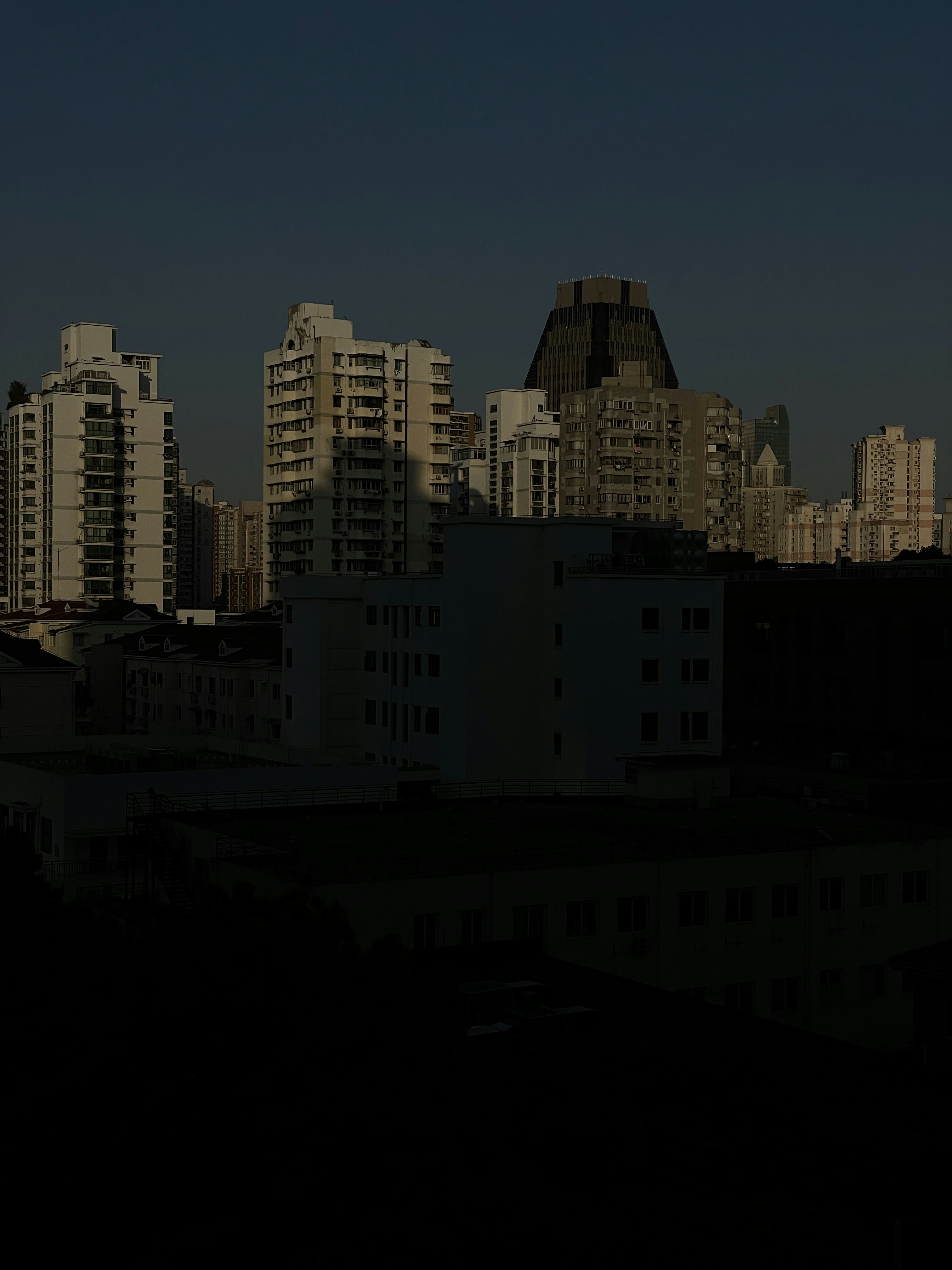Silhouetted skyline of modern buildings against a twilight sky, showcasing architectural diversity and urban life. 