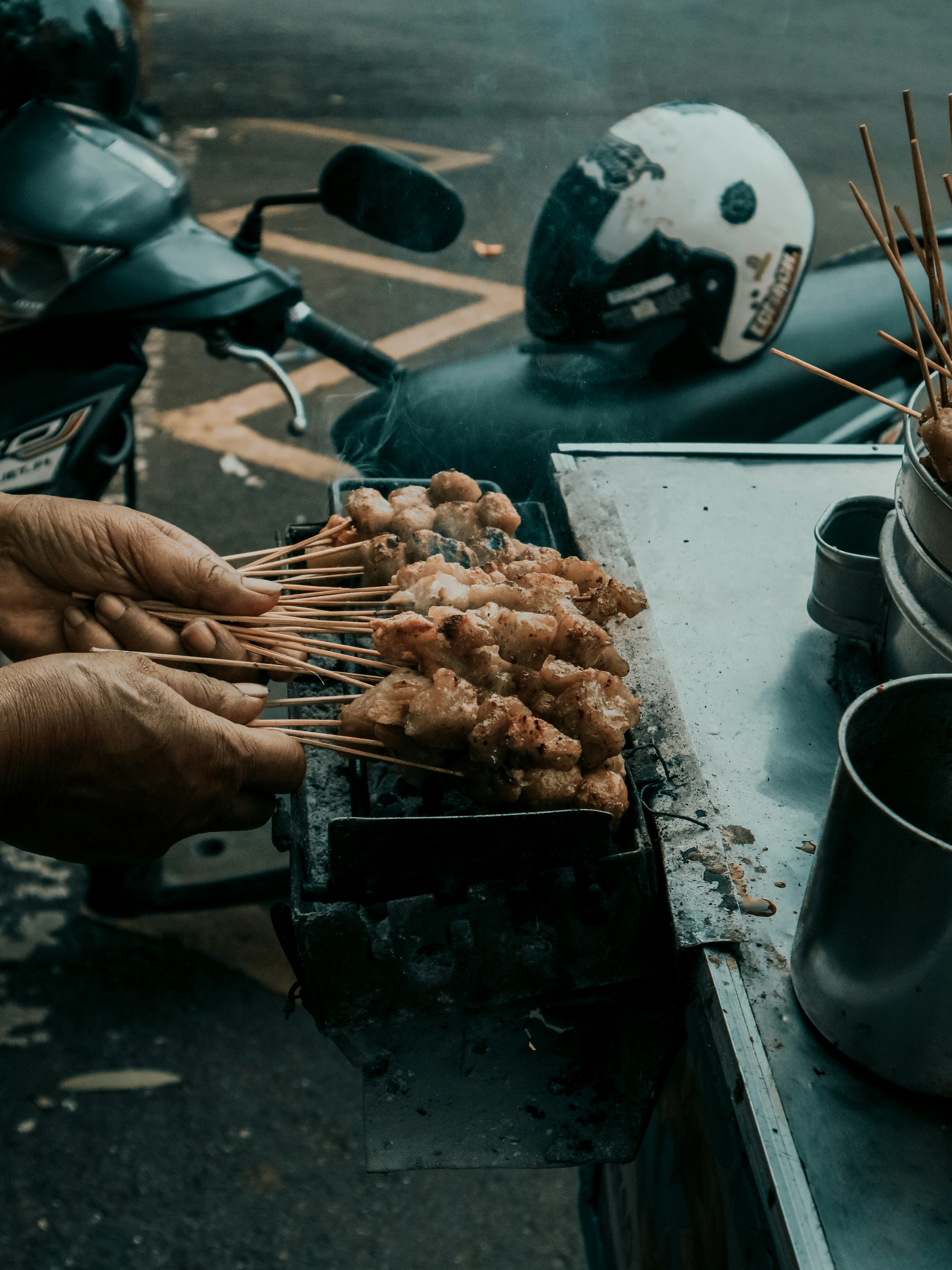 Charcoal Skewers on a Street Grill: Urban Flavor Under a Parked Motorcycle