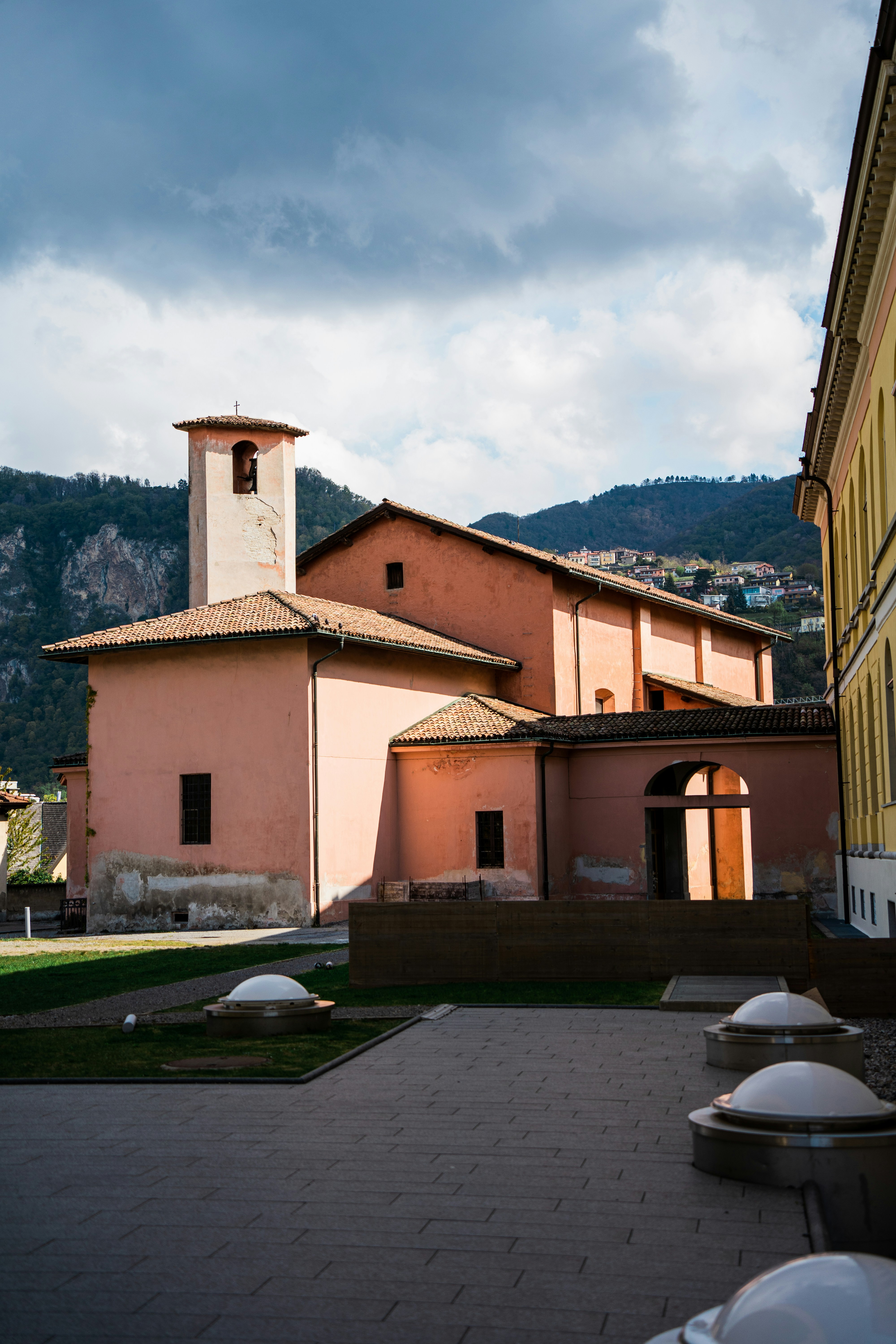 Pastel-Hued Chapel on a Hillside Under a Cloudy Sky