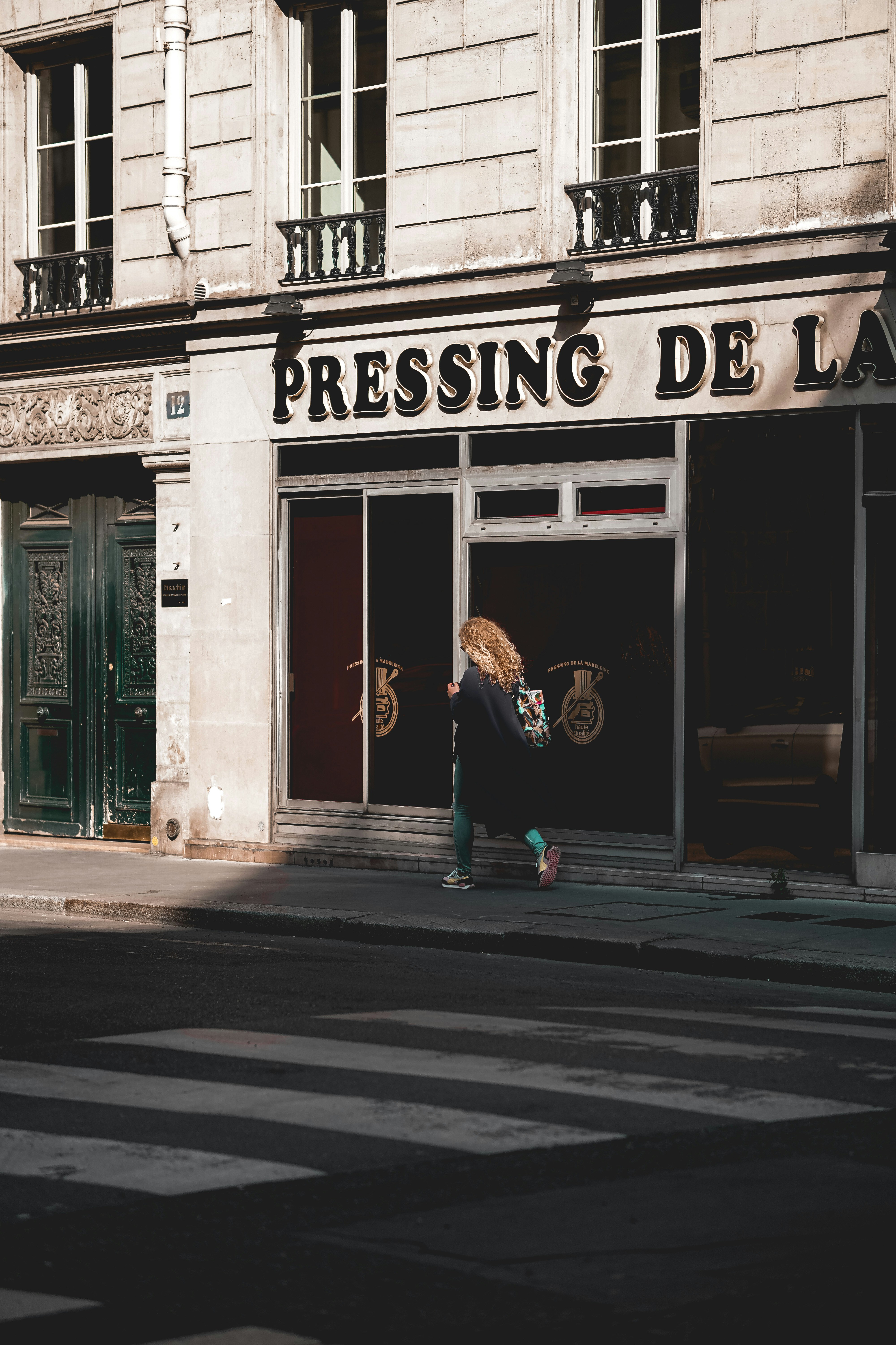Woman with curly hair entering a vintage Paris storefront at dusk